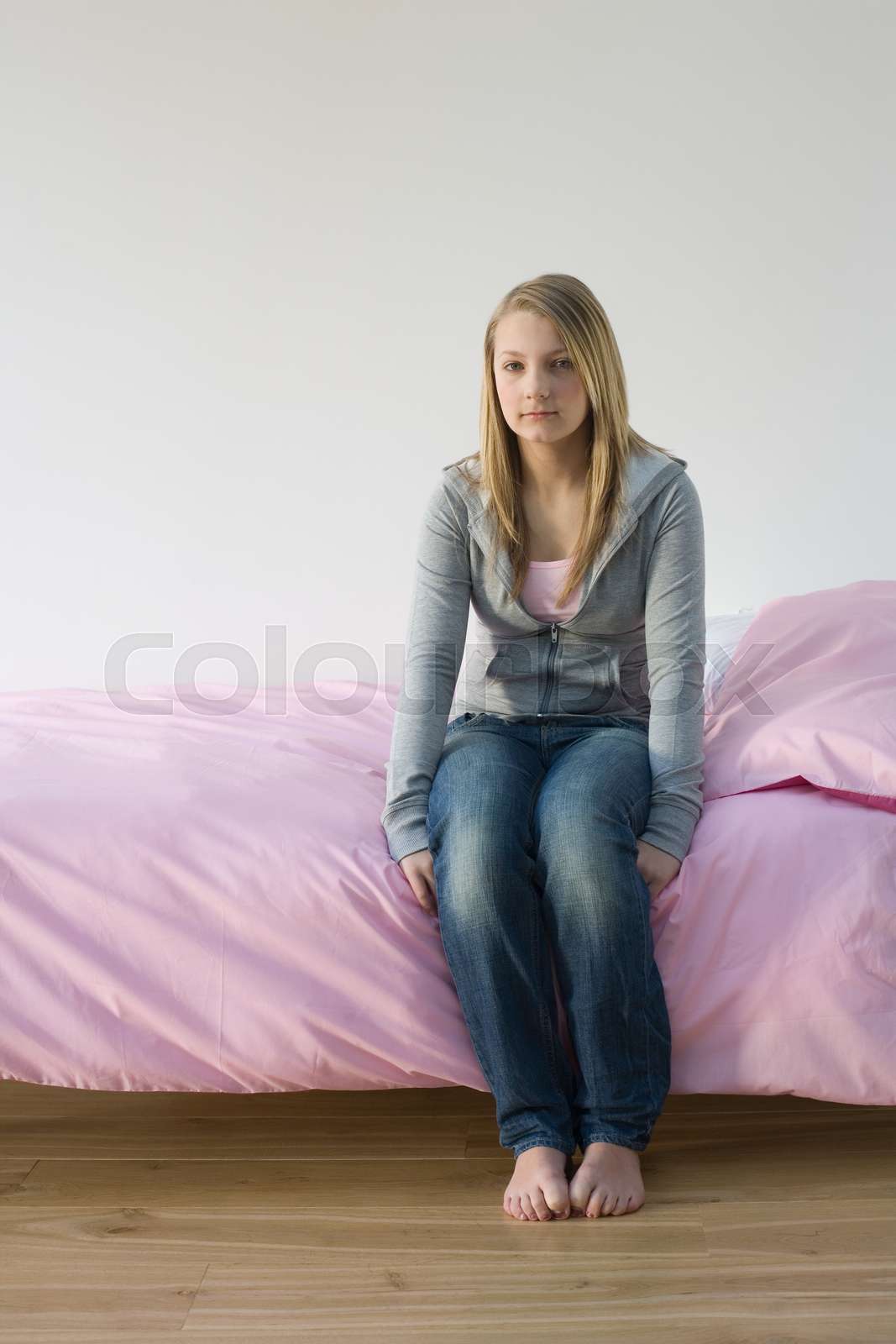 Portrait of a teenage girl sat on a bed | Stock image | Colourbox