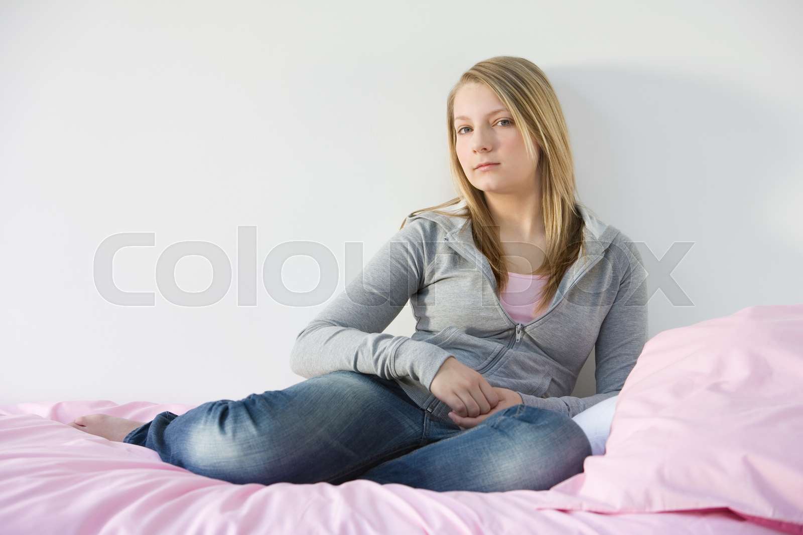 Portrait of a teenage girl sat on a bed | Stock image | Colourbox