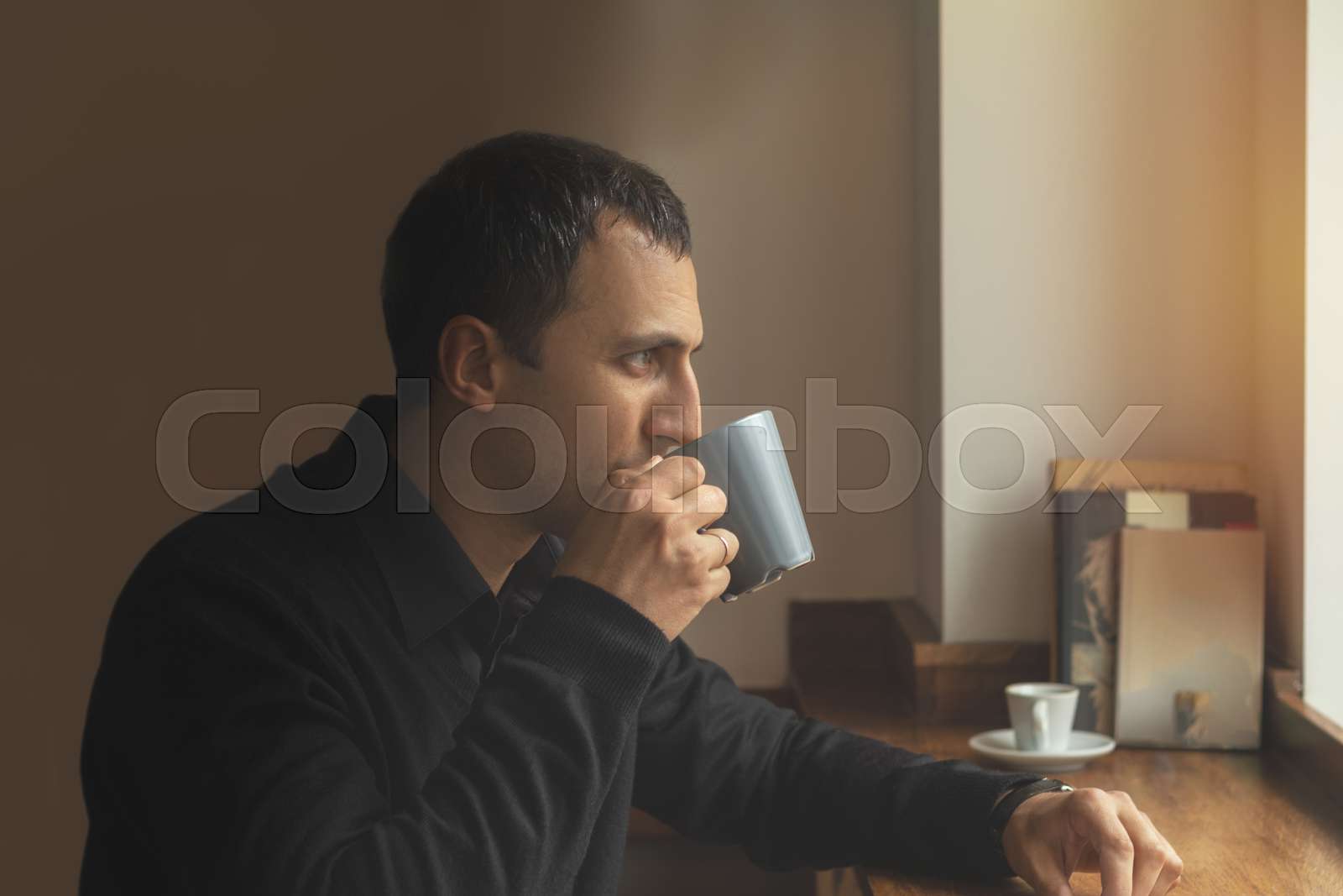 Young man in casual clothes drinks coffee while sitting in a cafe. Man ...