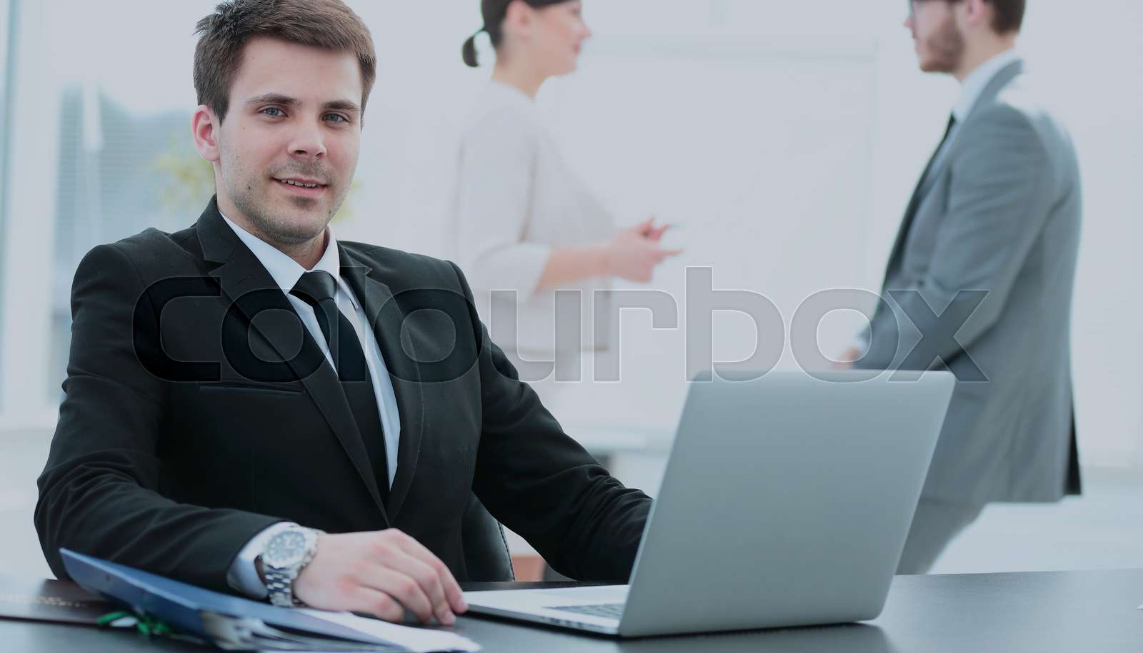 successful businessman sitting behind a Desk with an open laptop ...