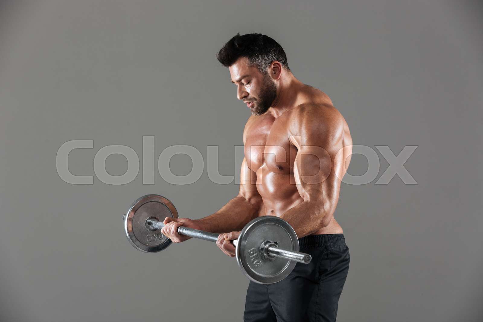 Side view of a concentrated strong shirtless male bodybuilder | Stock ...