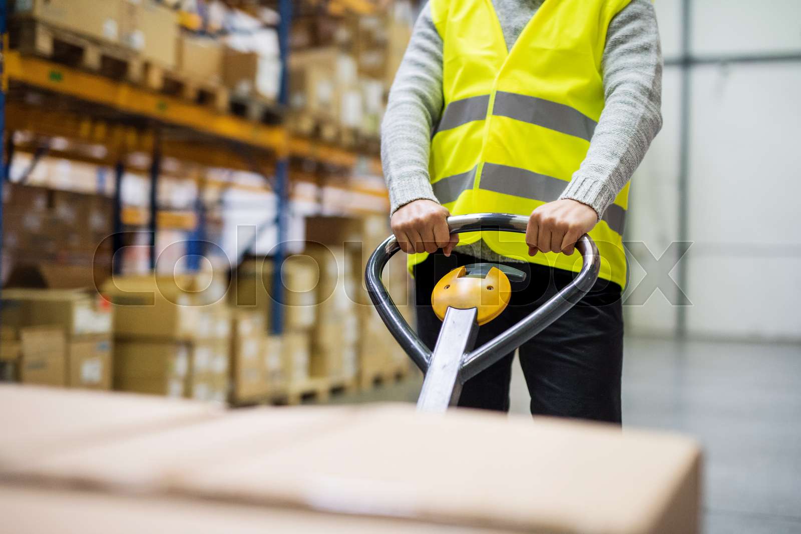 Male warehouse worker pulling a pallet truck. | Stock image | Colourbox