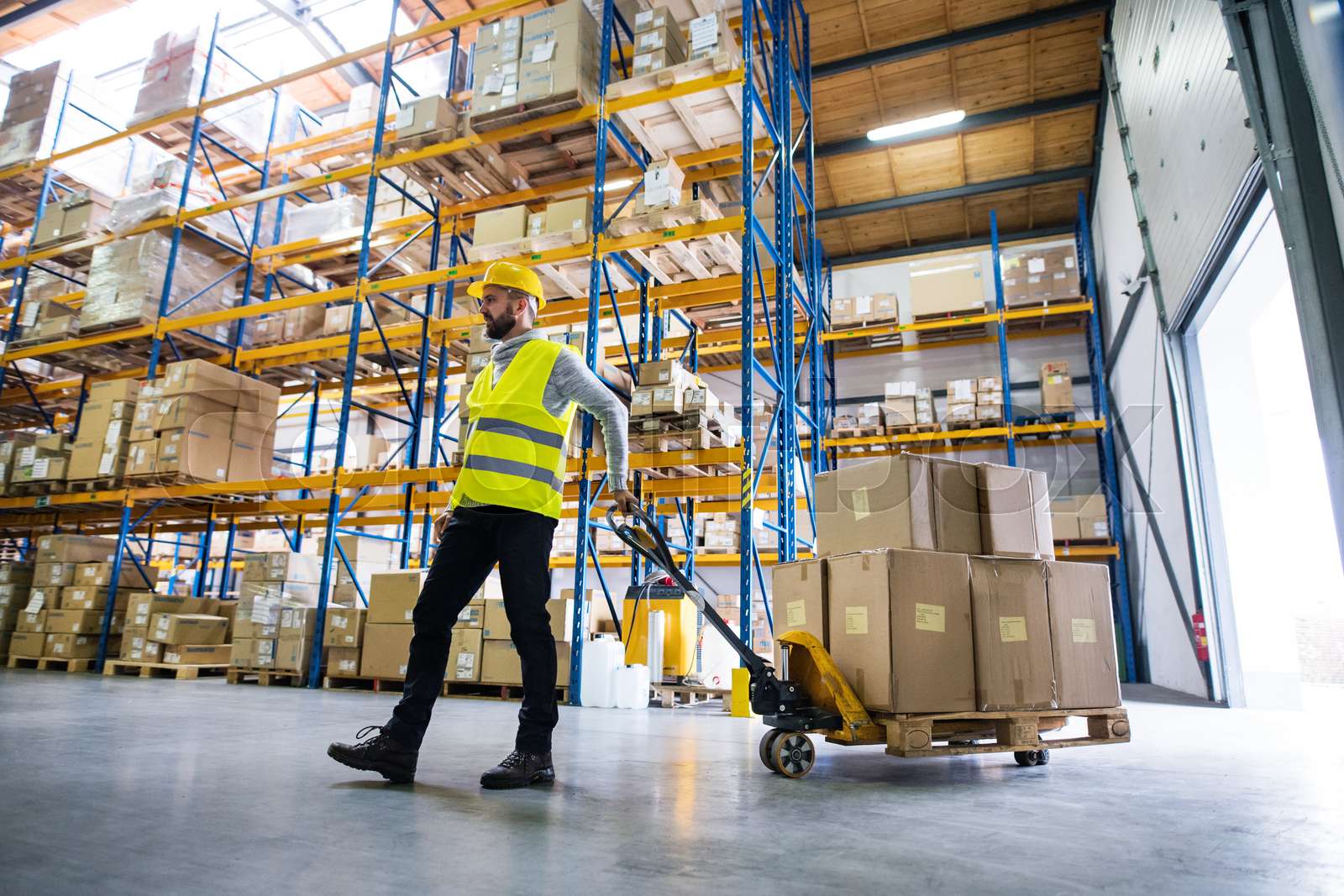 Male warehouse worker pulling a pallet truck. | Stock image | Colourbox