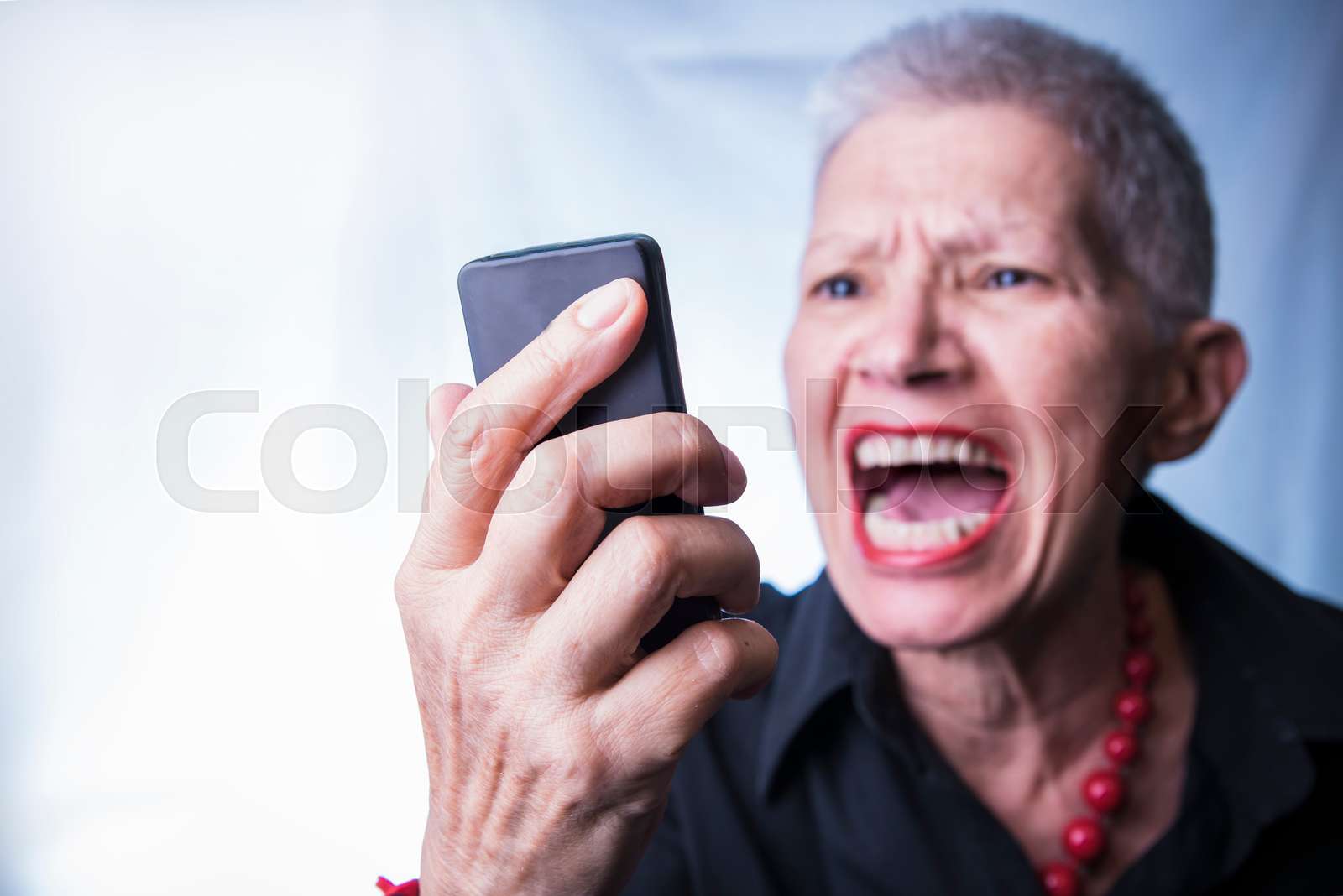 Old lady yelling at her cell phone | Stock image | Colourbox