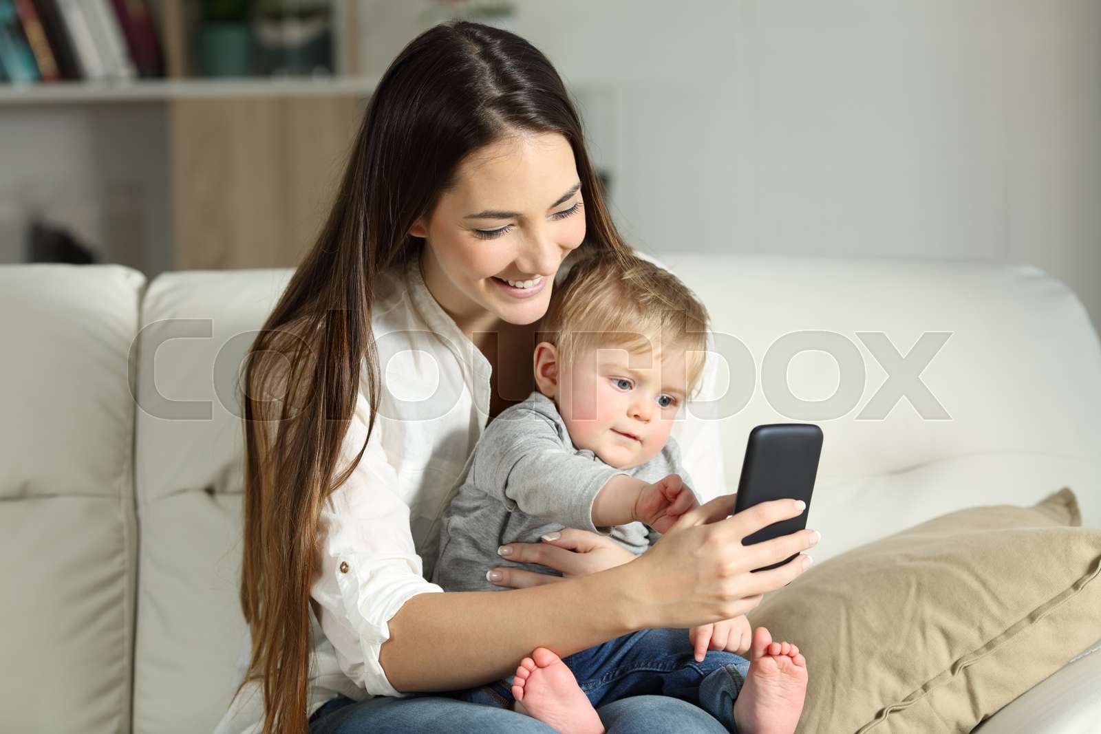 Mother and baby playing with a smart phone | Stock image | Colourbox