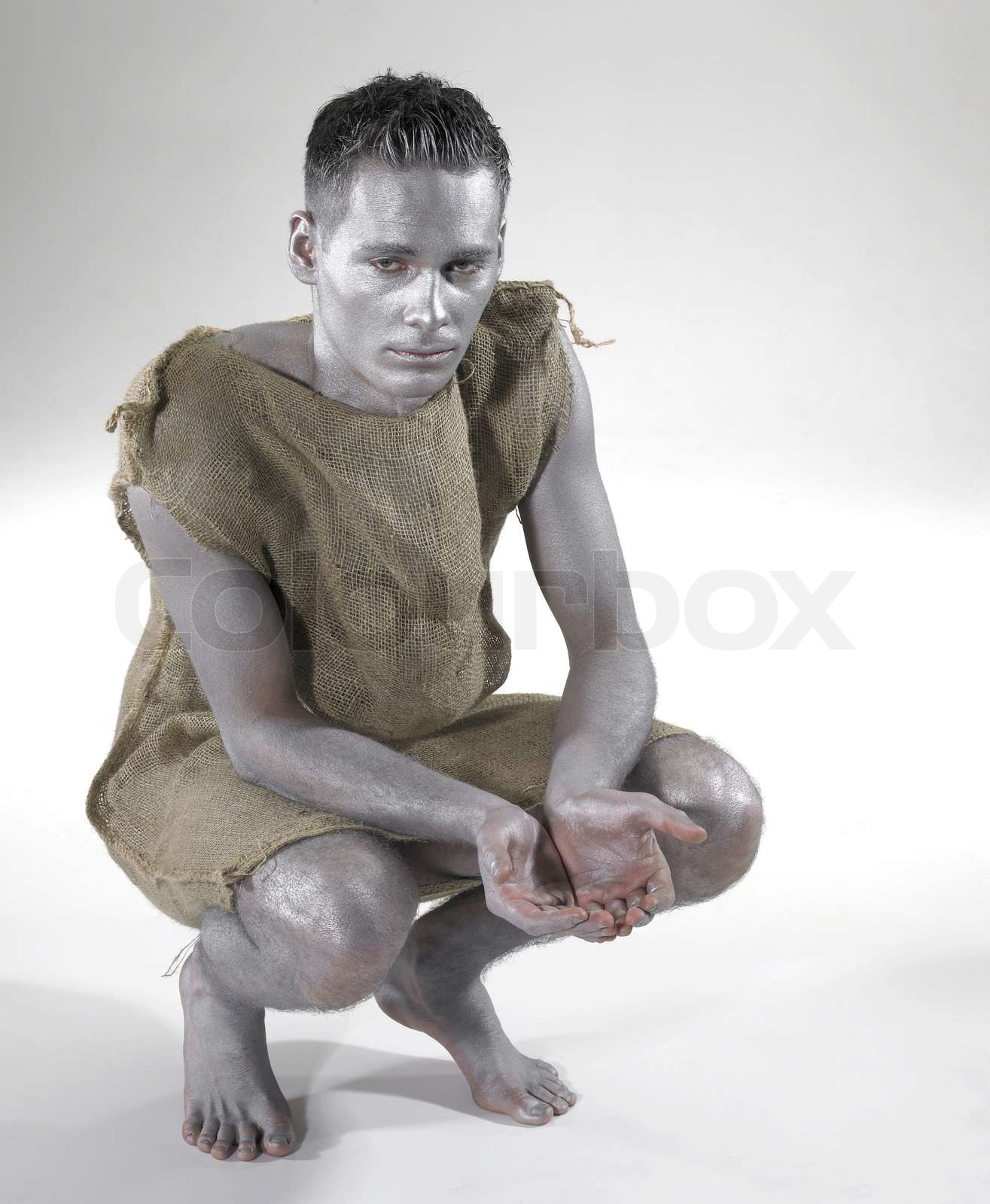 bodypainted poor man cowering on the ground | Stock image | Colourbox