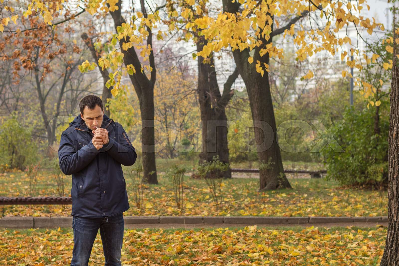 Handsome man walking in the autumn park. Man smoking cigarette in ...
