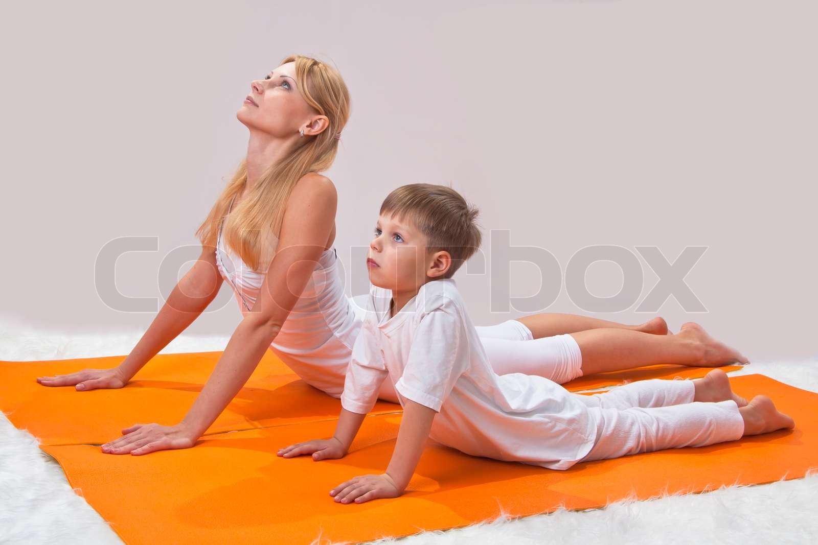 A Beautiful Young Mother Practices Yoga With Her Son Stock Image