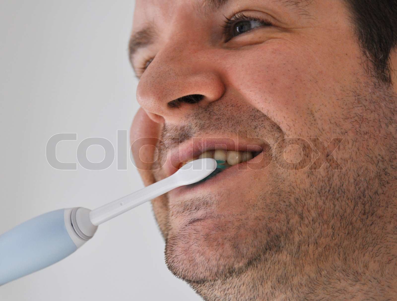 Man brushing his teeth with electric toothbrush, caucasian male with ...