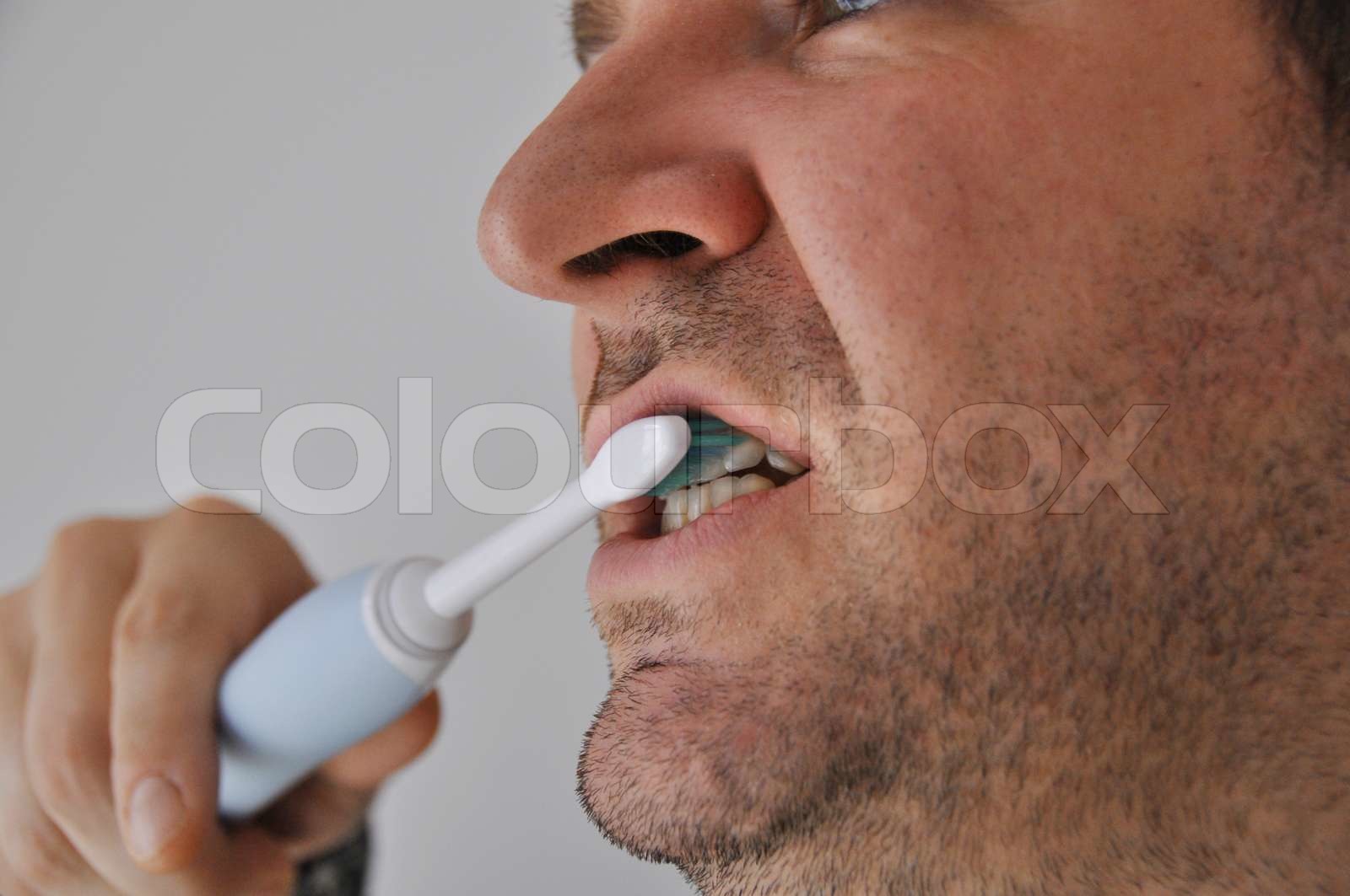 Man brushing his teeth with electric toothbrush, caucasian male with ...