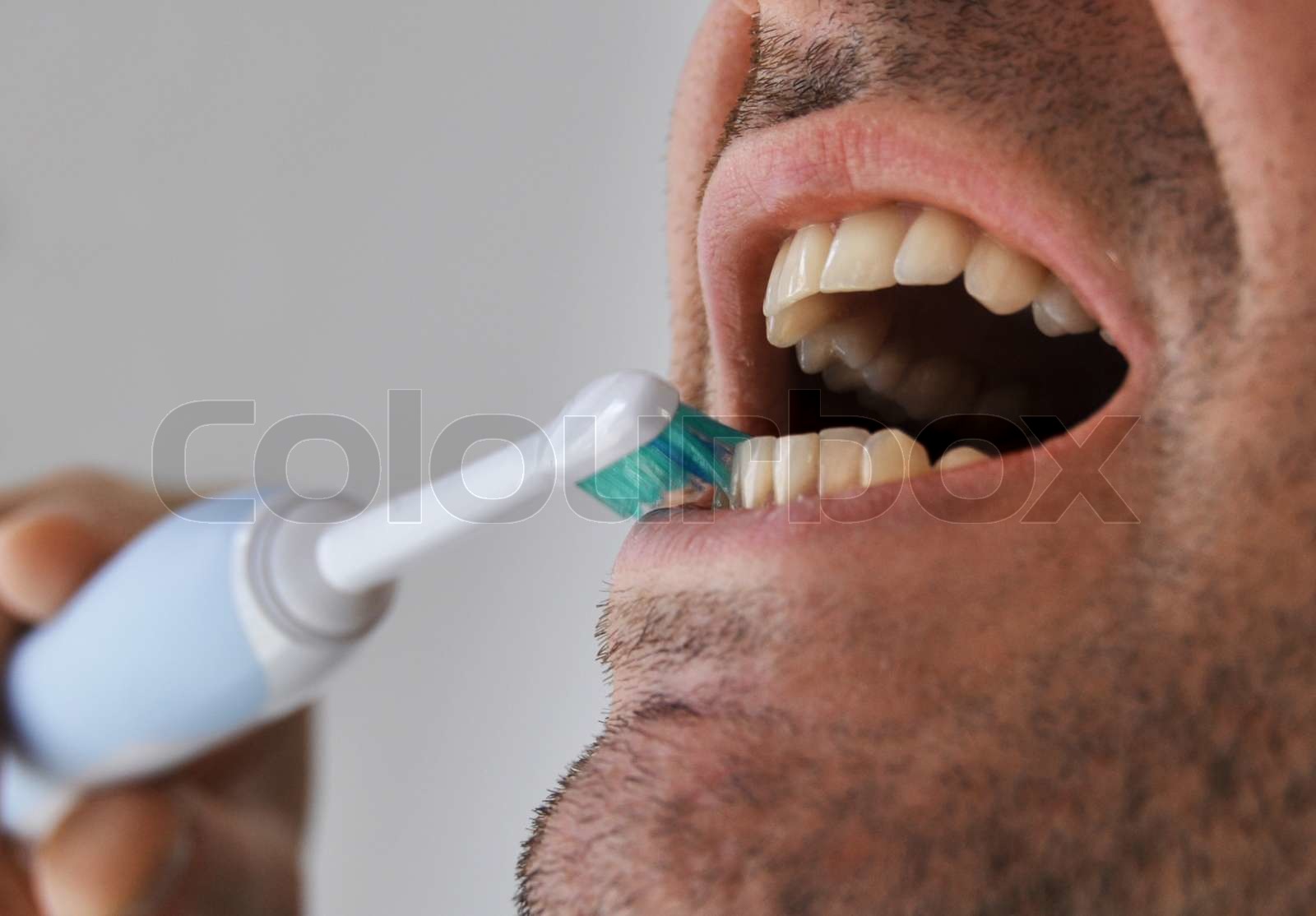 Man brushing his teeth with electric toothbrush, caucasian male with ...