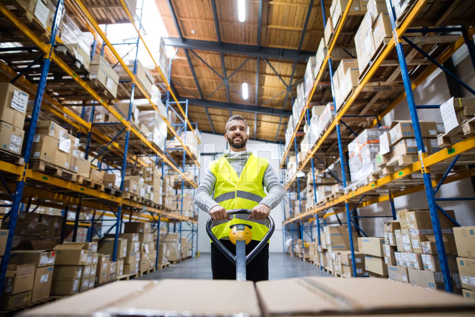 Male warehouse worker pulling a pallet truck. | Stock image | Colourbox