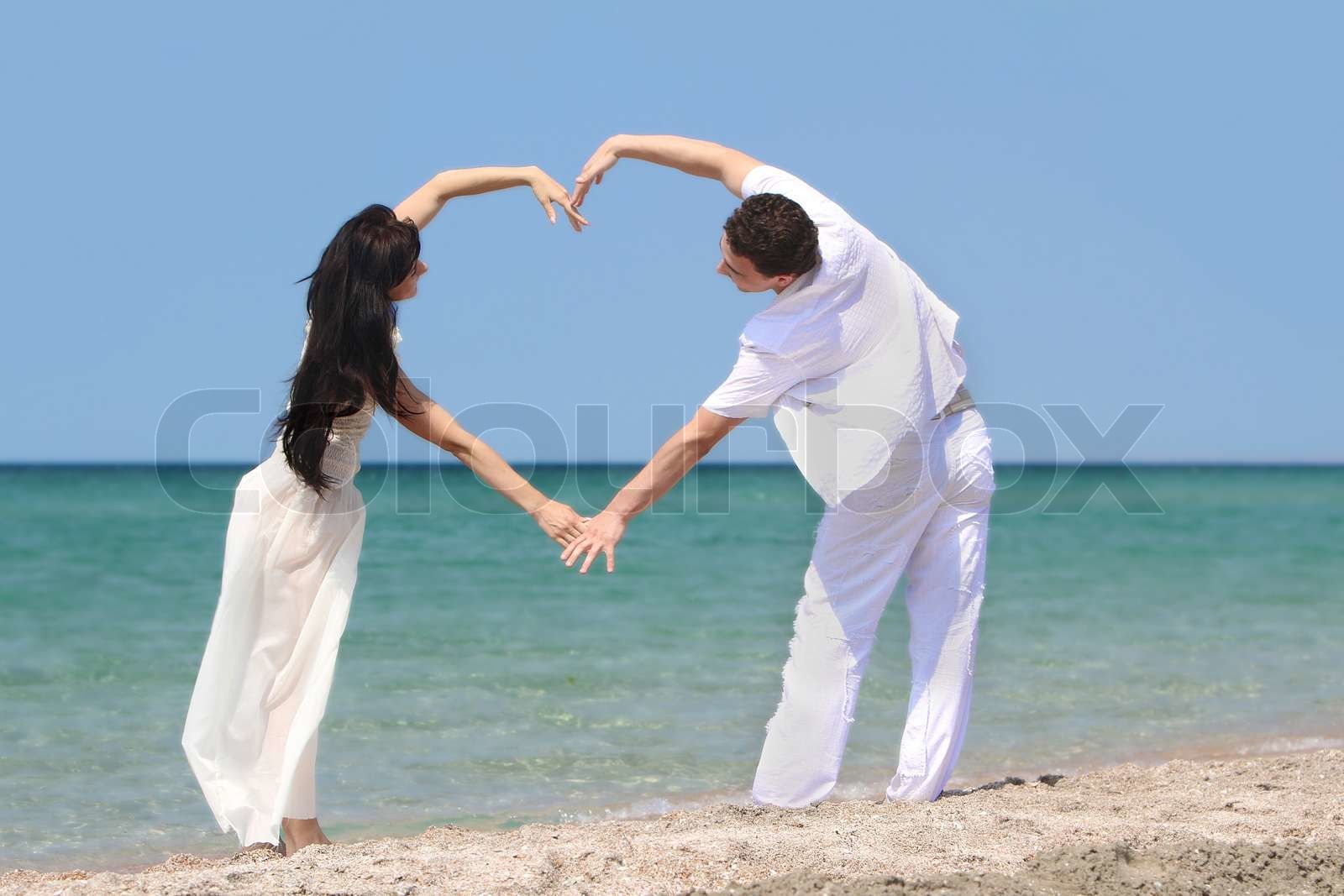 ungt par gør hjerte af våben på stranden | Stock foto | Colourbox