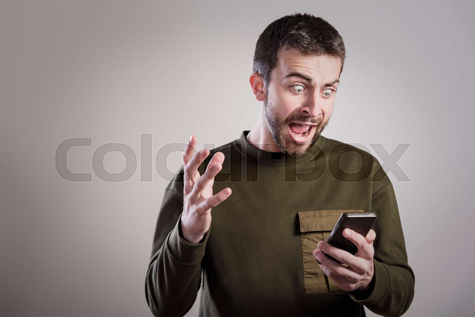 Man angry at his phone, outraged and enraged | Stock image | Colourbox