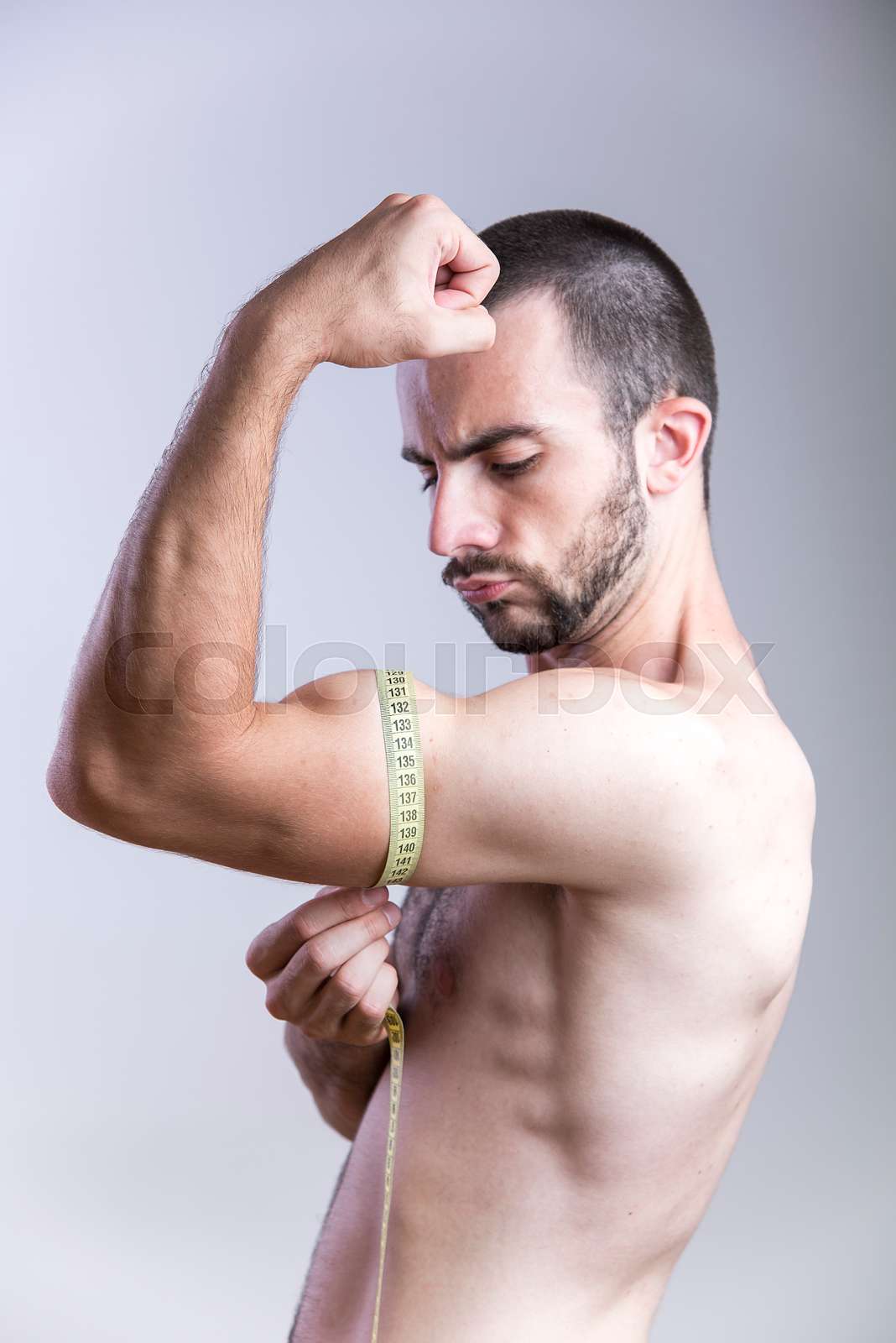 Man measuring his biceps size | Stock image | Colourbox