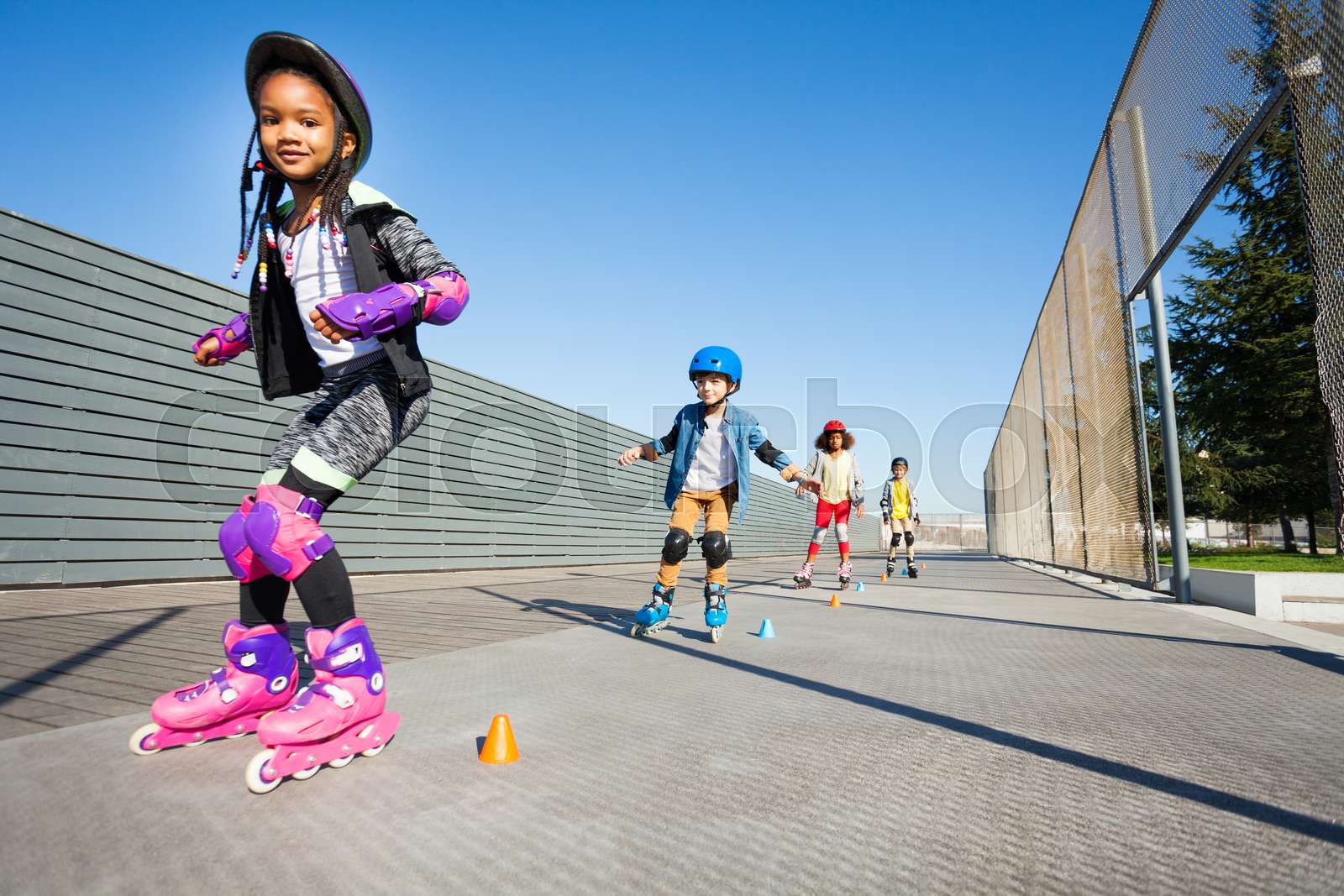Cute African girl learning to rollerblade outdoor | Stock image | Colourbox