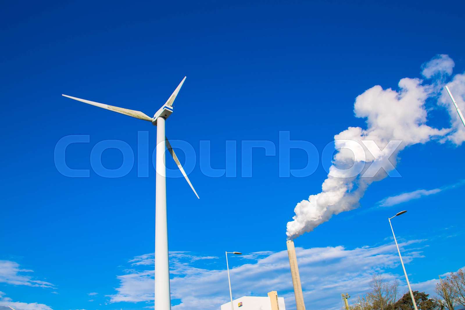 Wind turbine and factory chimney | Stock image | Colourbox