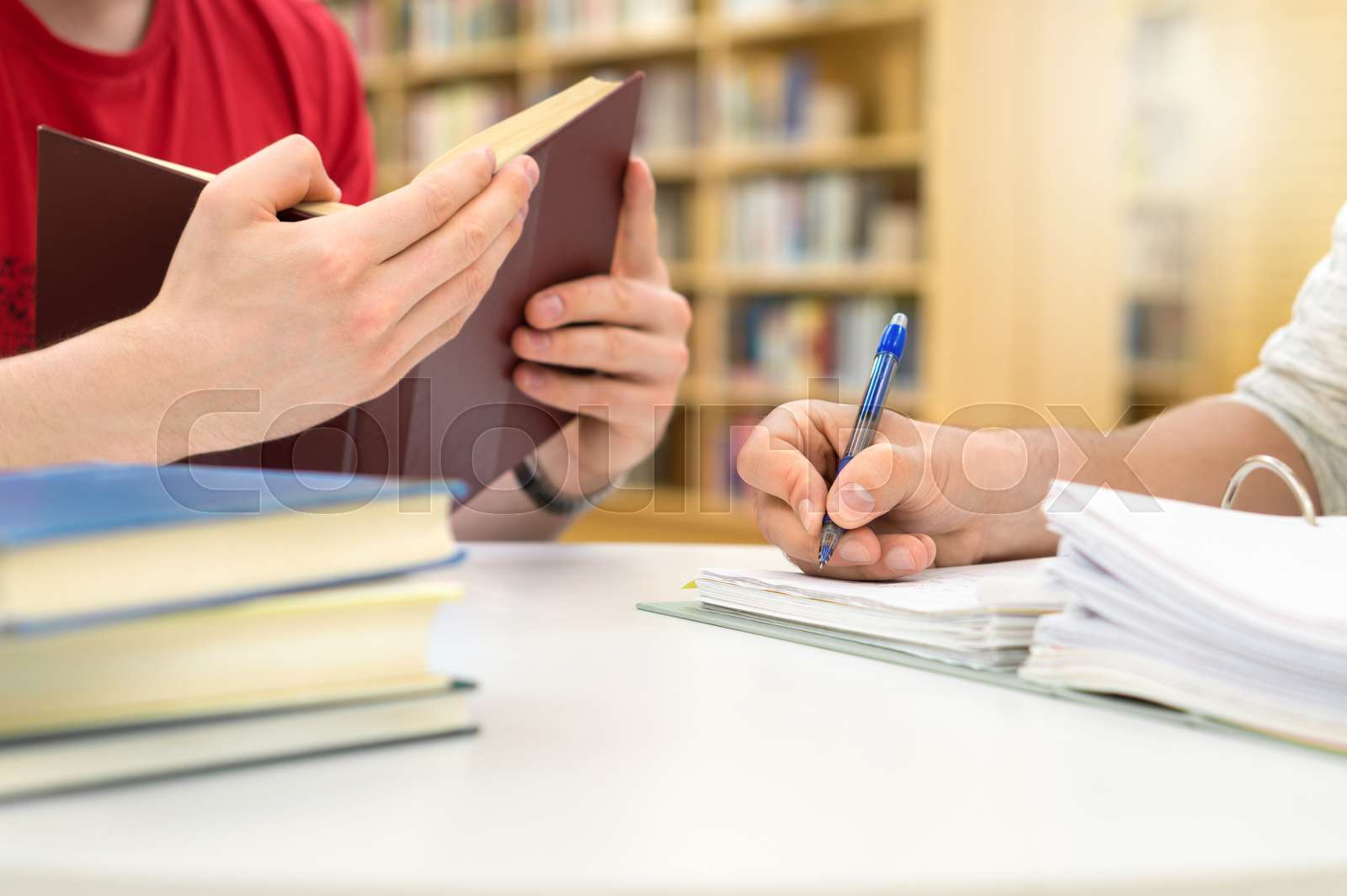 Two students studying, reading and writing in library. | Stock image ...