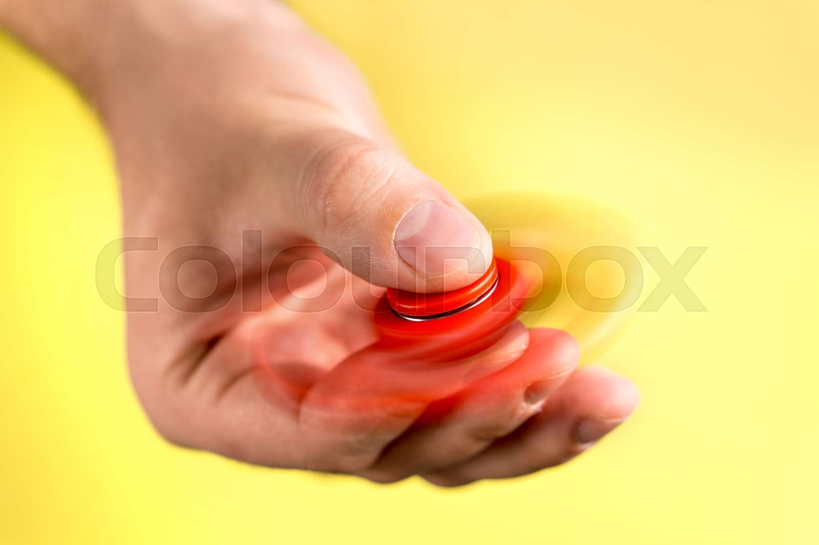 Red fidget spinner spinning fast between fingers | Stock image | Colourbox