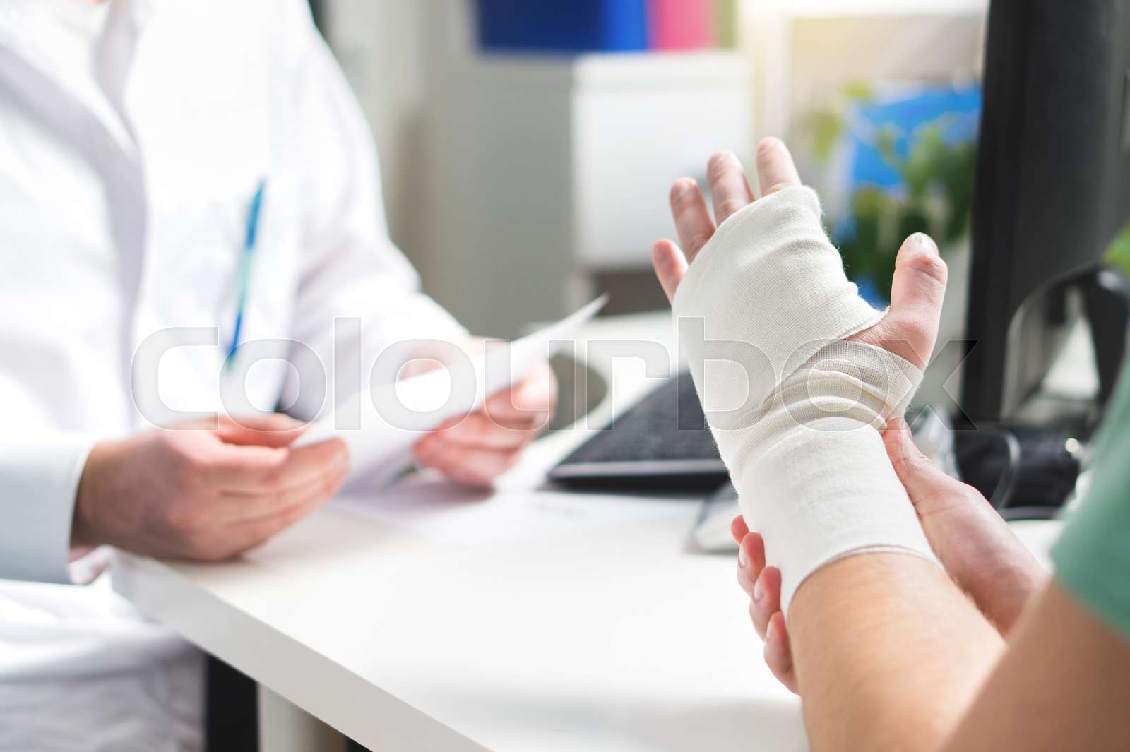 Injured patient showing doctor broken wrist and arm with bandage in ...