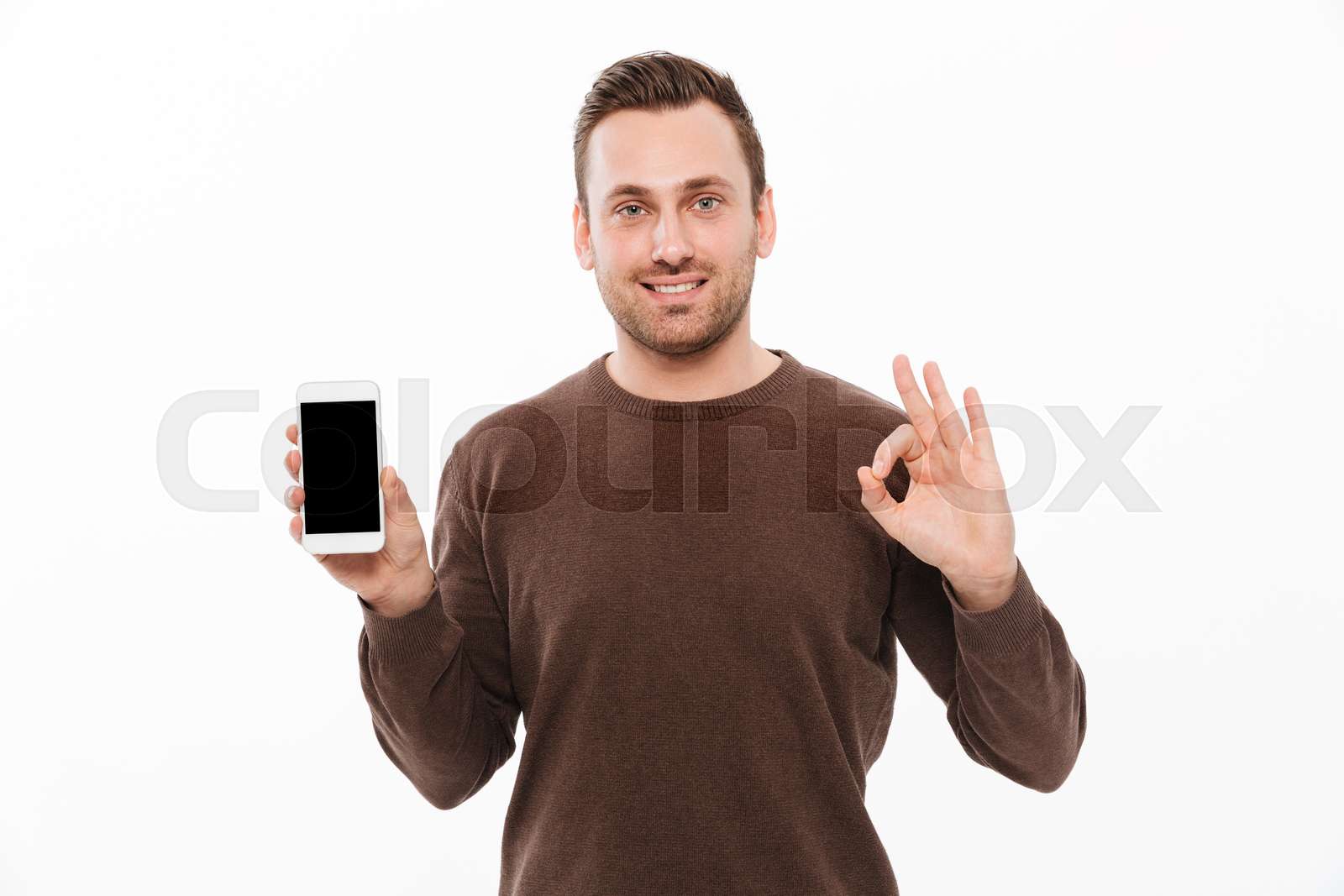 Happy young man showing display of mobile phone | Stock image | Colourbox
