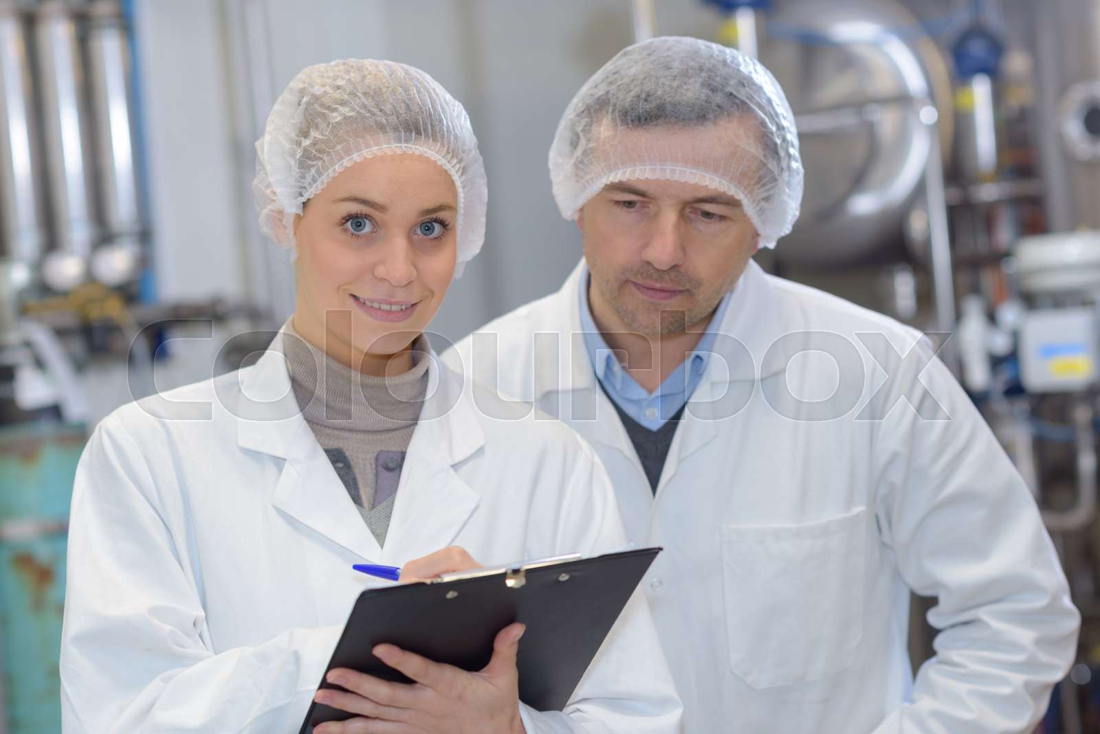 Man and woman wearing hair nets making notes on clipboard | Stock image ...