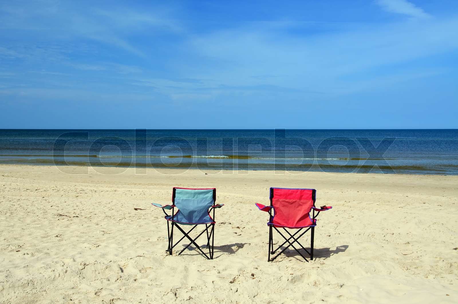 A blue and a pink beach chair facing the ocean | Stock image | Colourbox