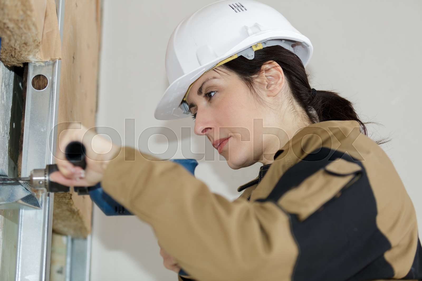 Female contractor using electric drill | Stock image | Colourbox