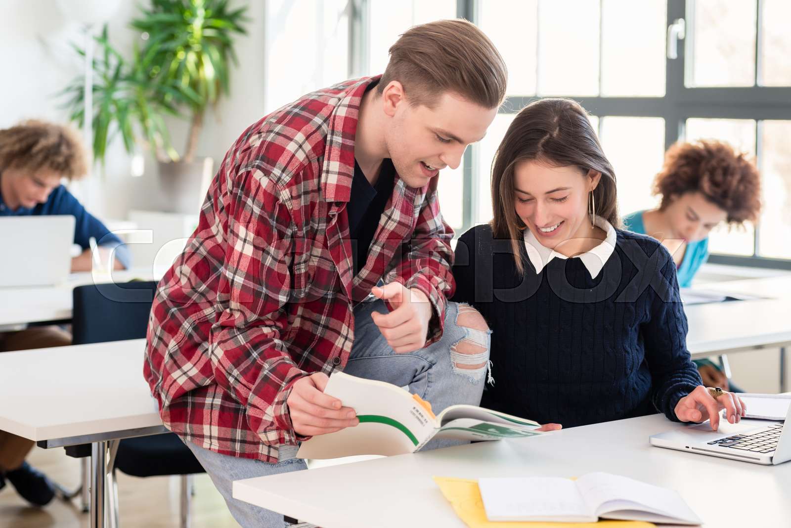 Friendly student helping his classmate by explaining and showing the ...