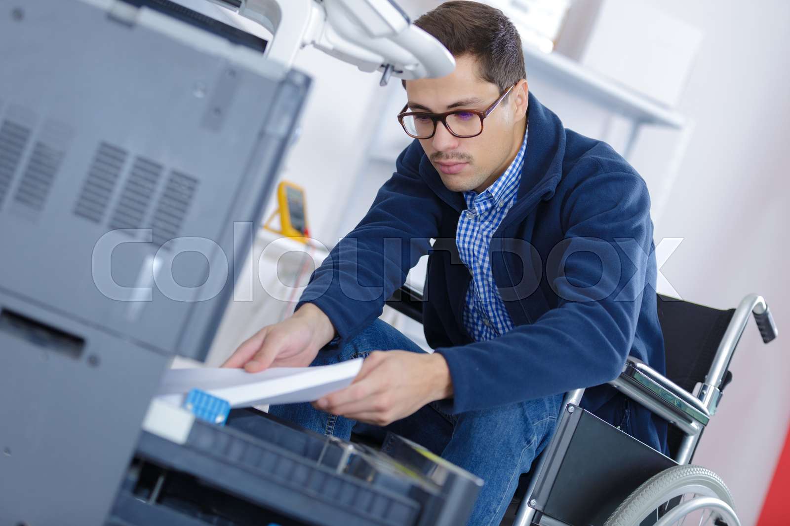 wheelchair worker putting a stack of paper into printer | Stock image ...