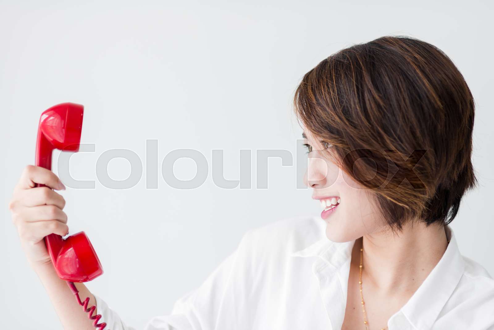 Beautiful woman wearing white shirt and hold red vintage phone against ...