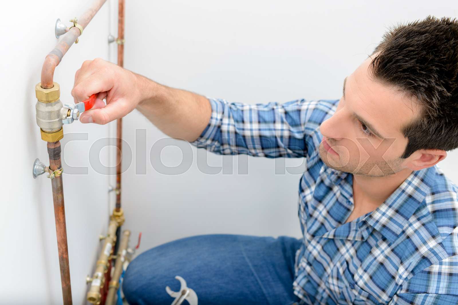 Man turning lever on pipework | Stock image | Colourbox