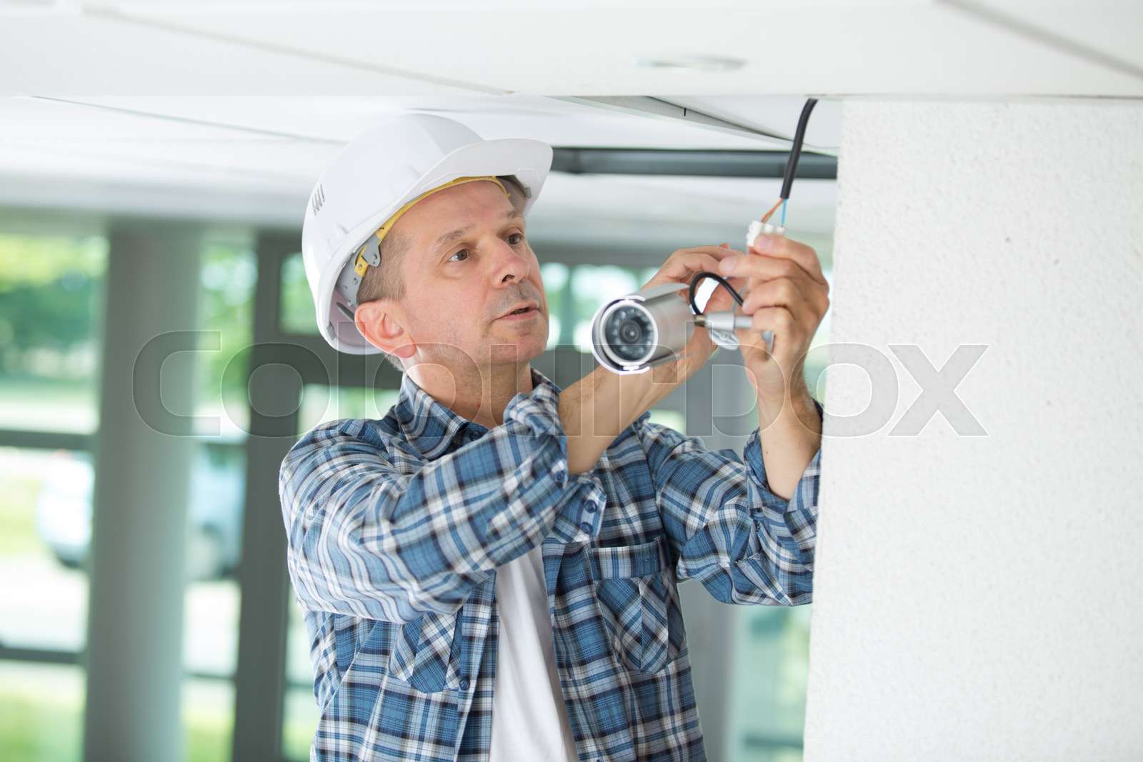 male worker inspecting security camera | Stock image | Colourbox