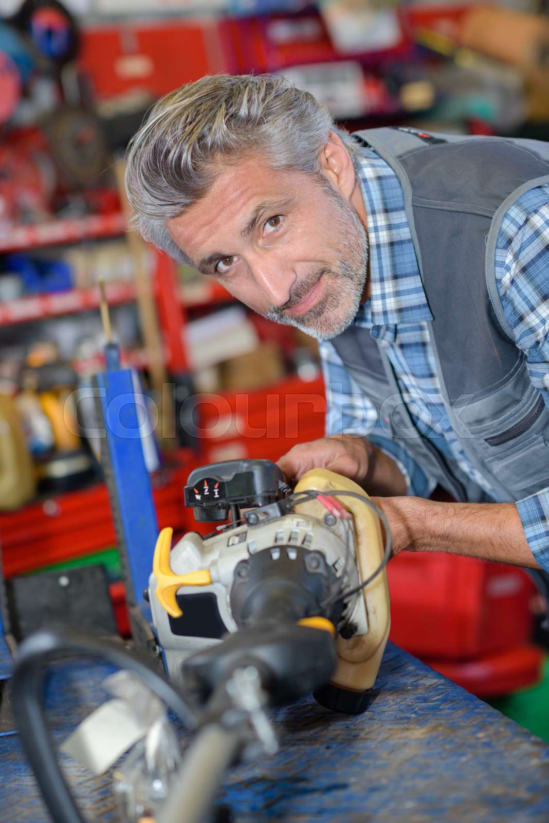 mature man repairing weed whacking machine | Stock image | Colourbox