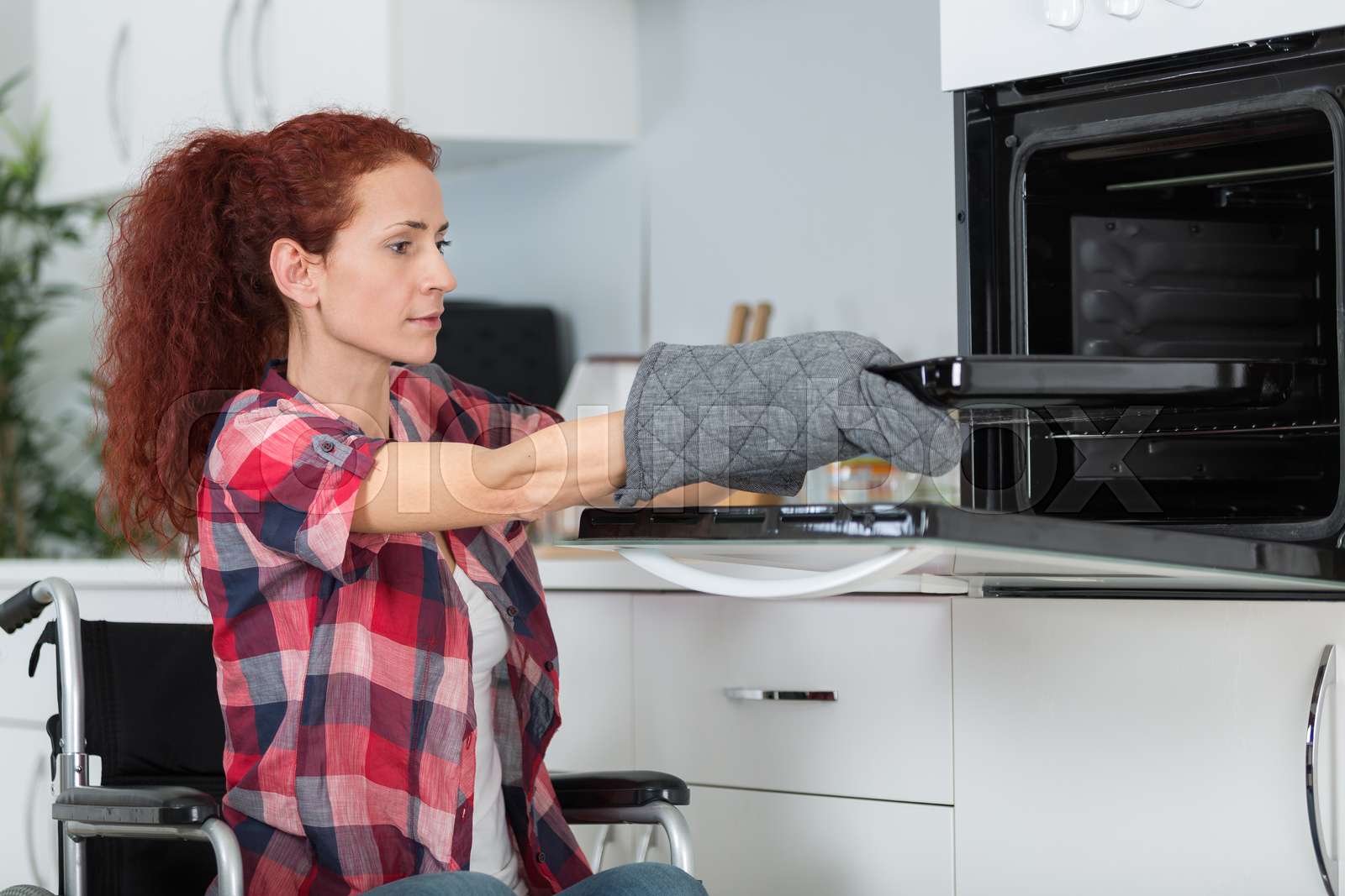 disabled adult woman in wheelchair cooking dinner | Stock image | Colourbox