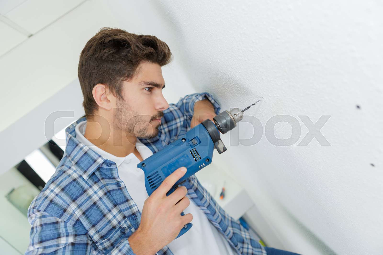 male builder drilling holes in wall at construction site | Stock image ...
