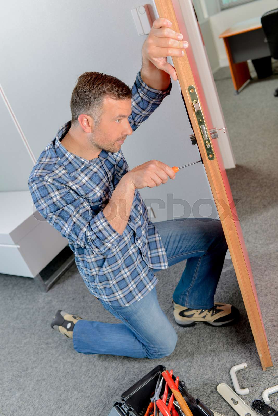 Man fixing lock to interior door | Stock image | Colourbox