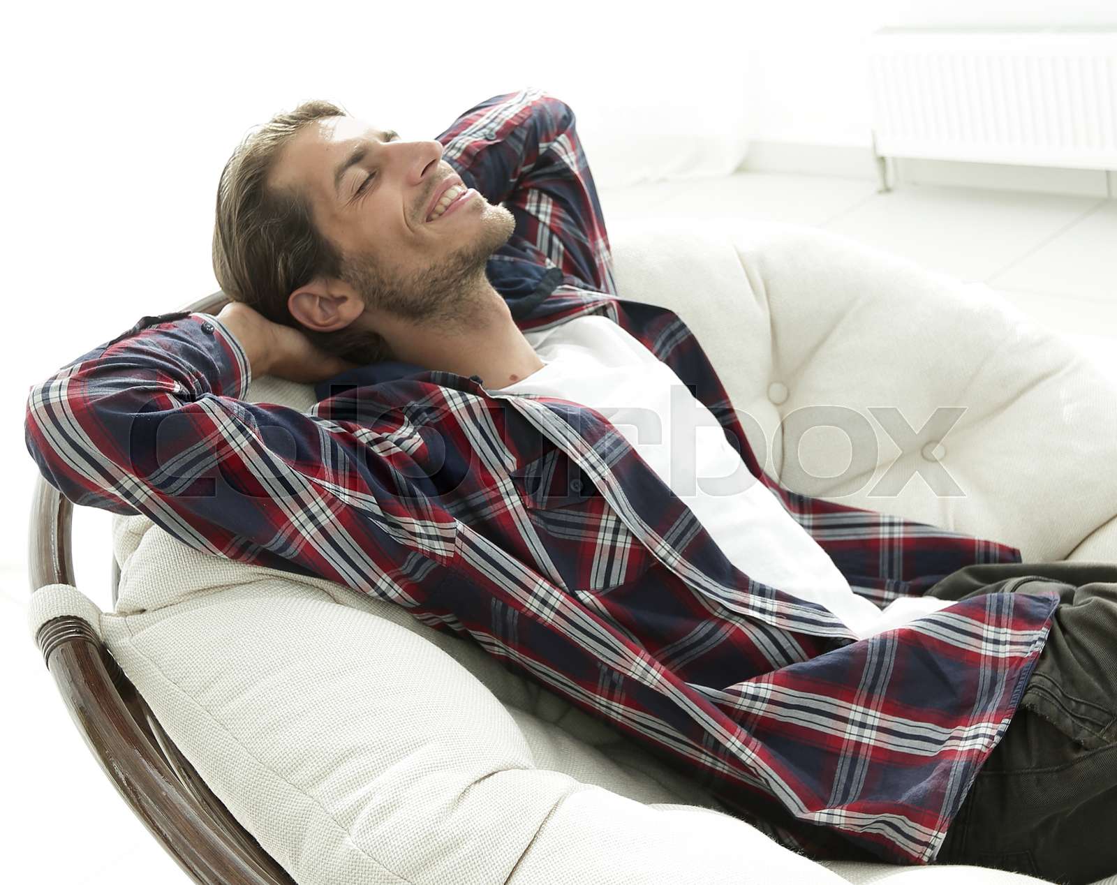 modern guy is resting sitting in a large comfortable chair. side view ...