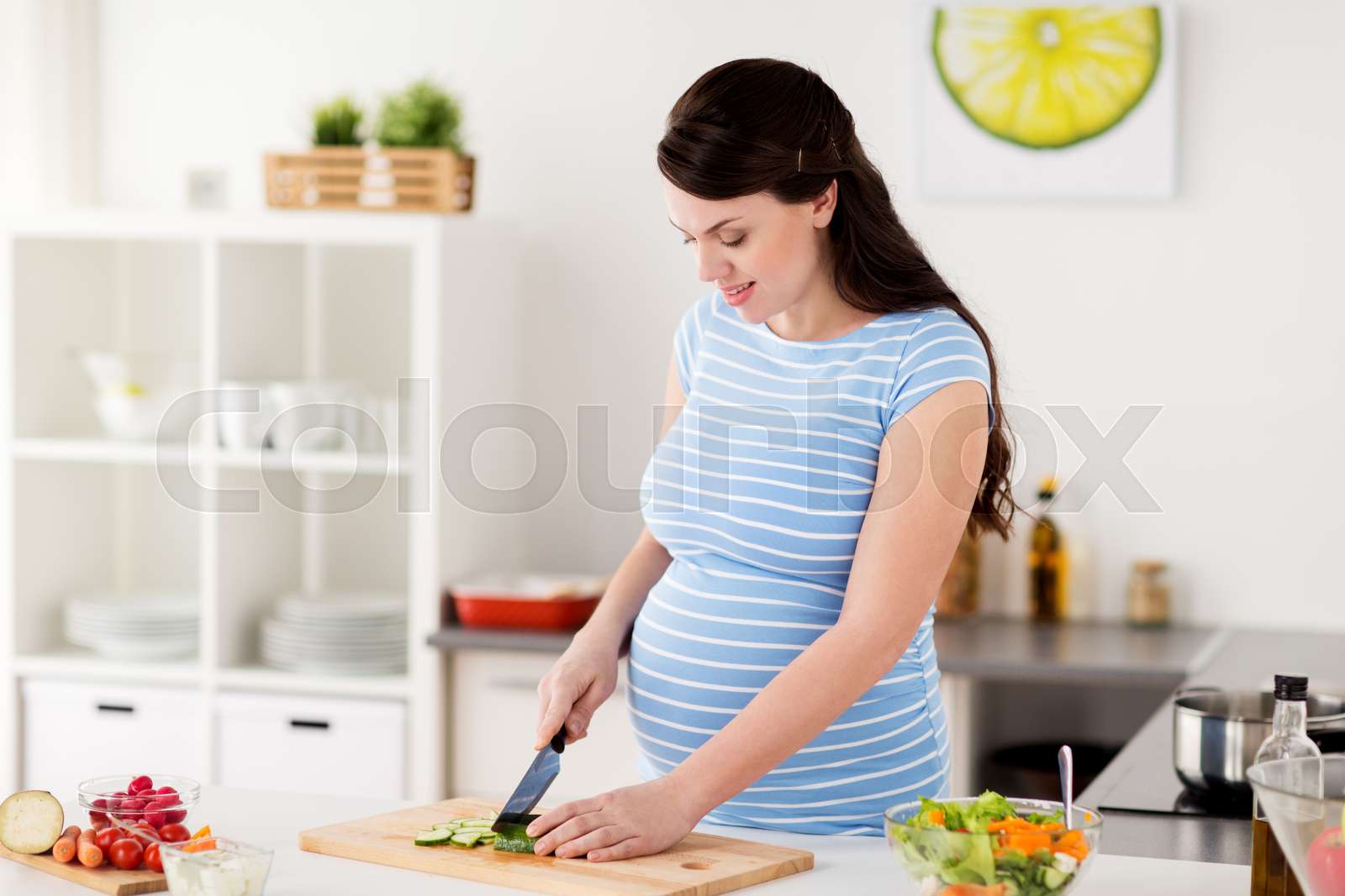 pregnant woman cooking vegetables at home | Stock image | Colourbox