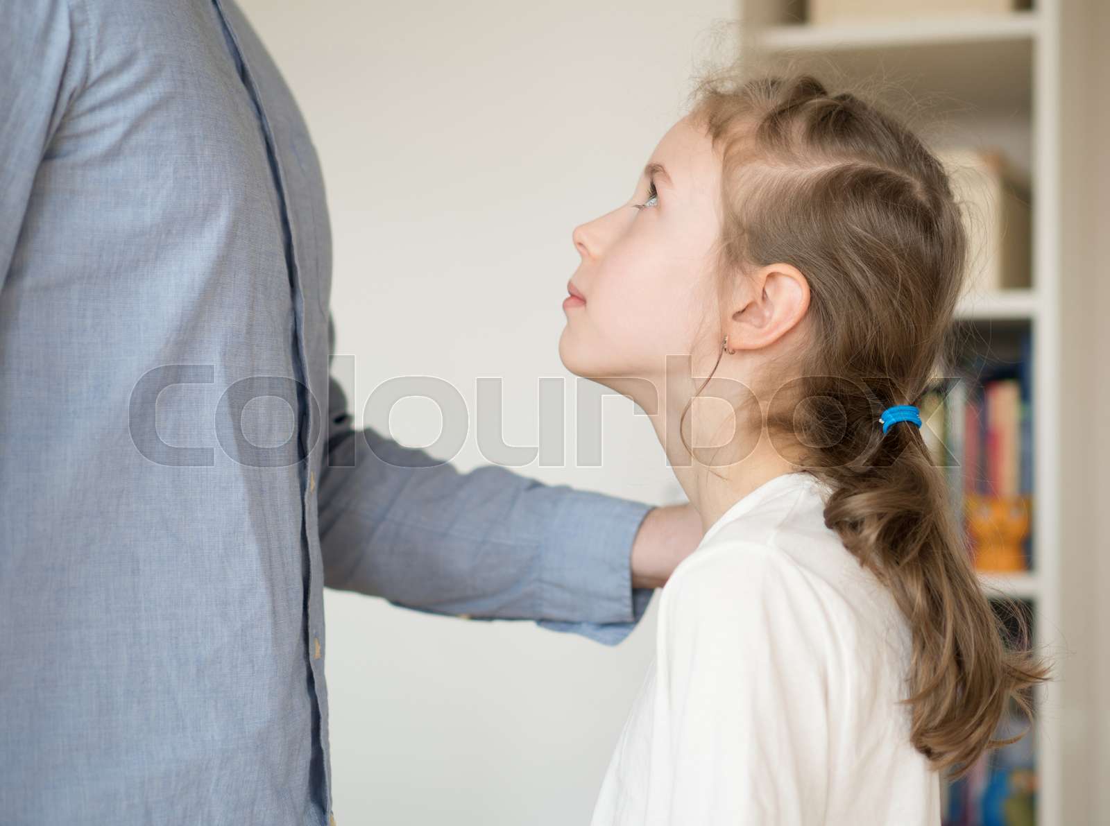 Sad little girl standing in front of her father and looking at him ...