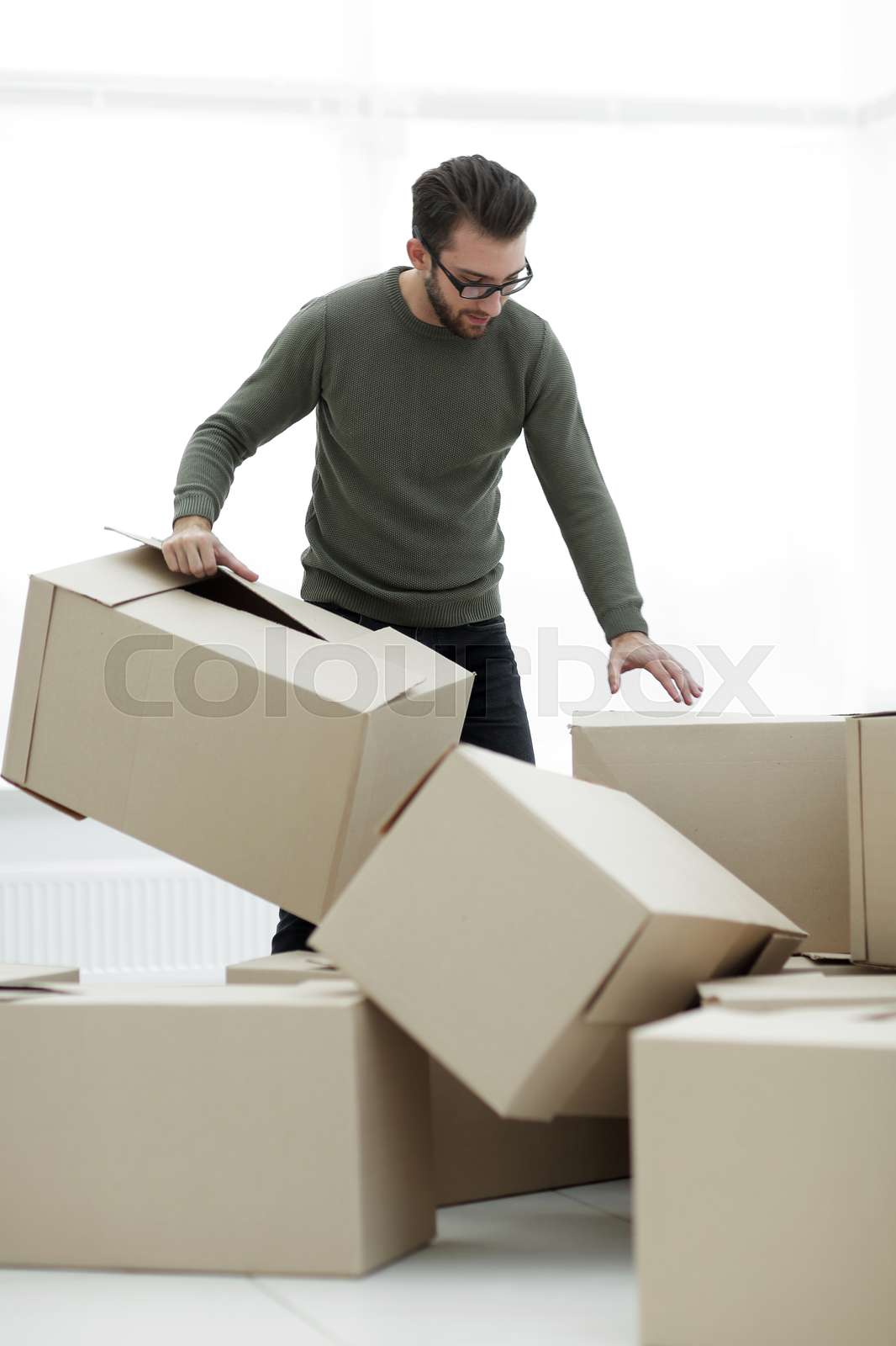 confident man unpacking boxes in the new house | Stock image | Colourbox