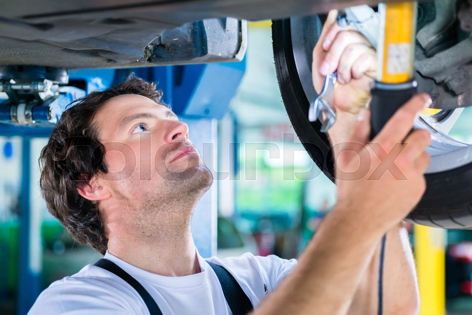 Mechanic working in car workshop on wheel | Stock image | Colourbox