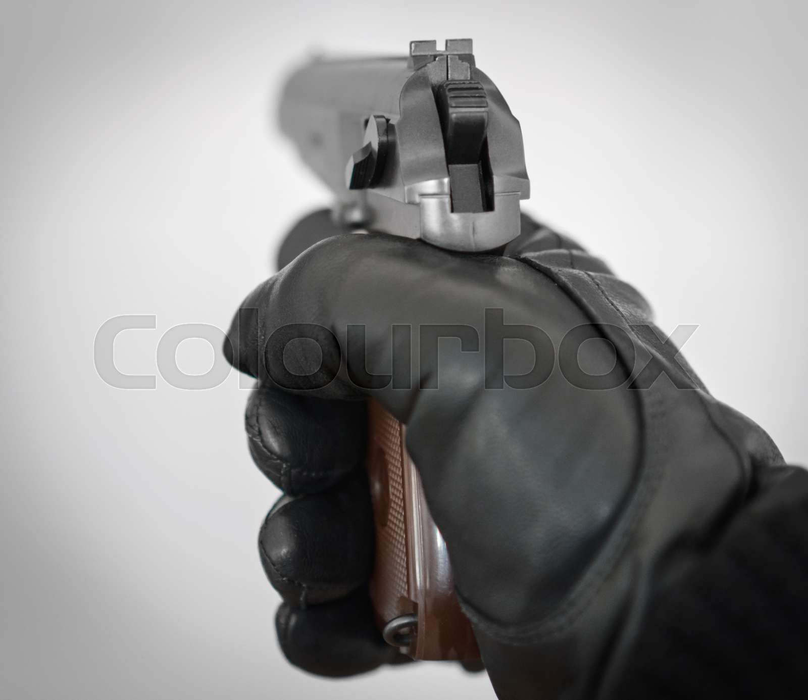 Hand in leather glove holding gun and aiming. | Stock image | Colourbox