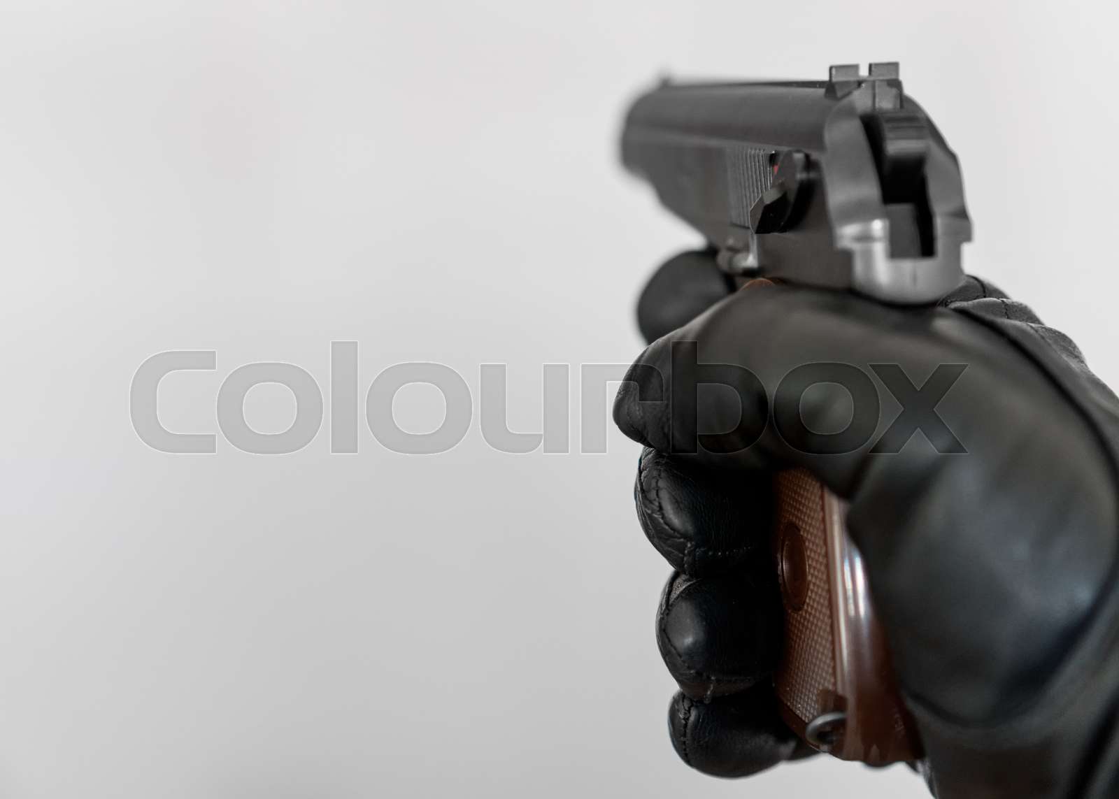 Hand in leather glove holding gun and aiming. | Stock image | Colourbox