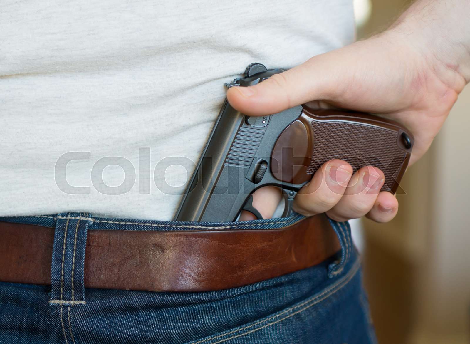 Man hiding gun behind his back. | Stock image | Colourbox