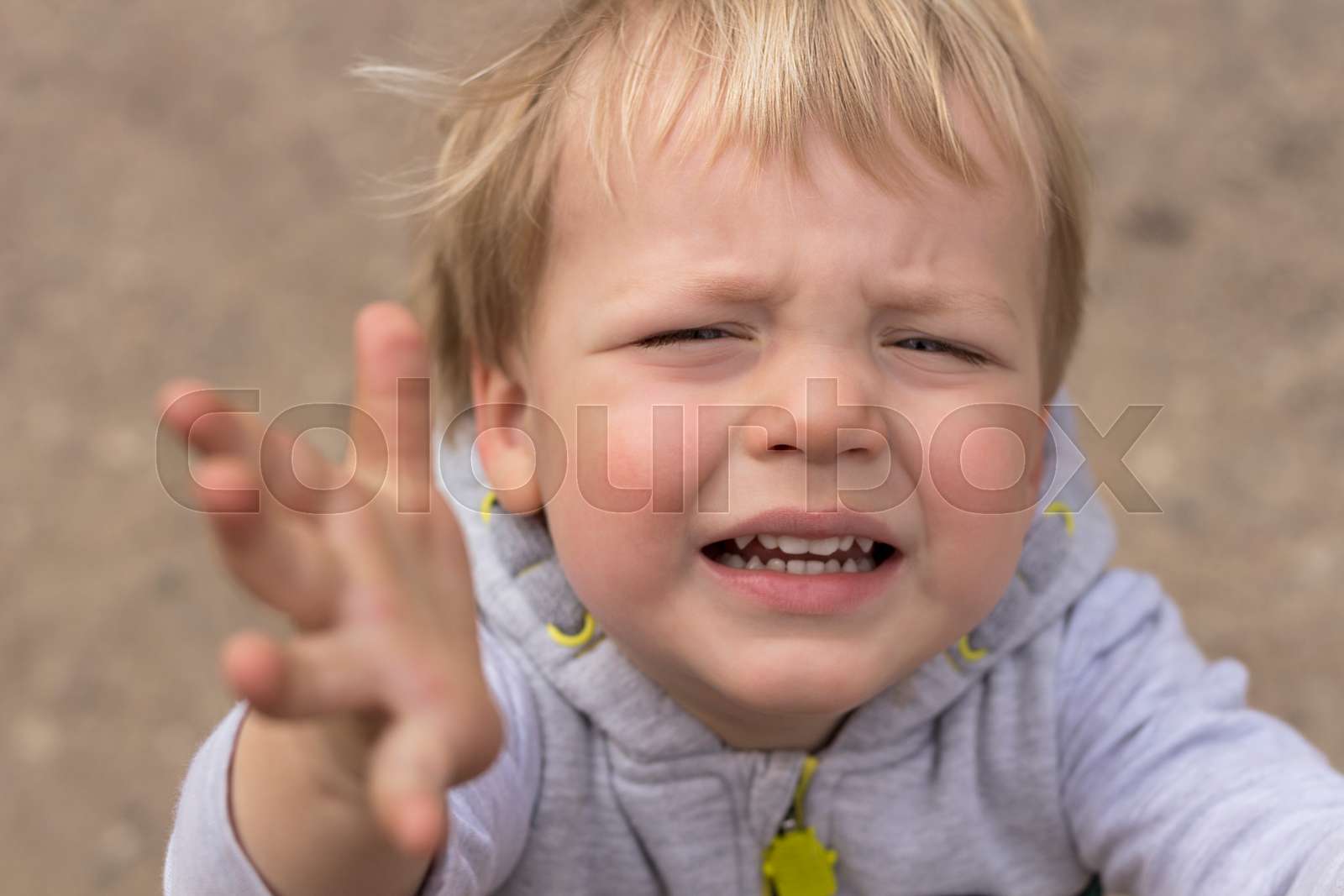 Sad crying toddler pulls his hands up. Close up portrait of baby boy ...