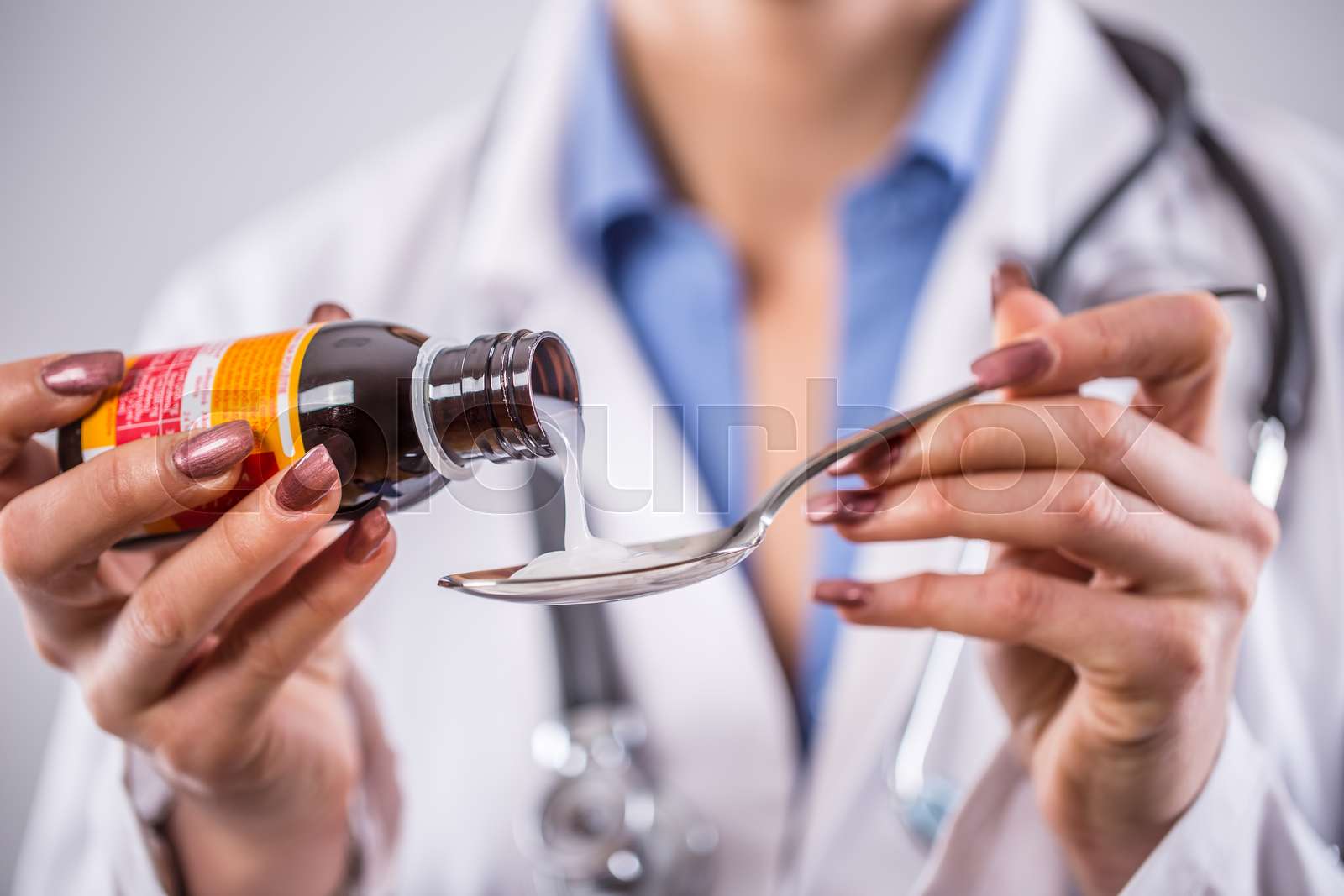 Hands of young woman doctor pouring medicinal syrup on spoon | Stock ...