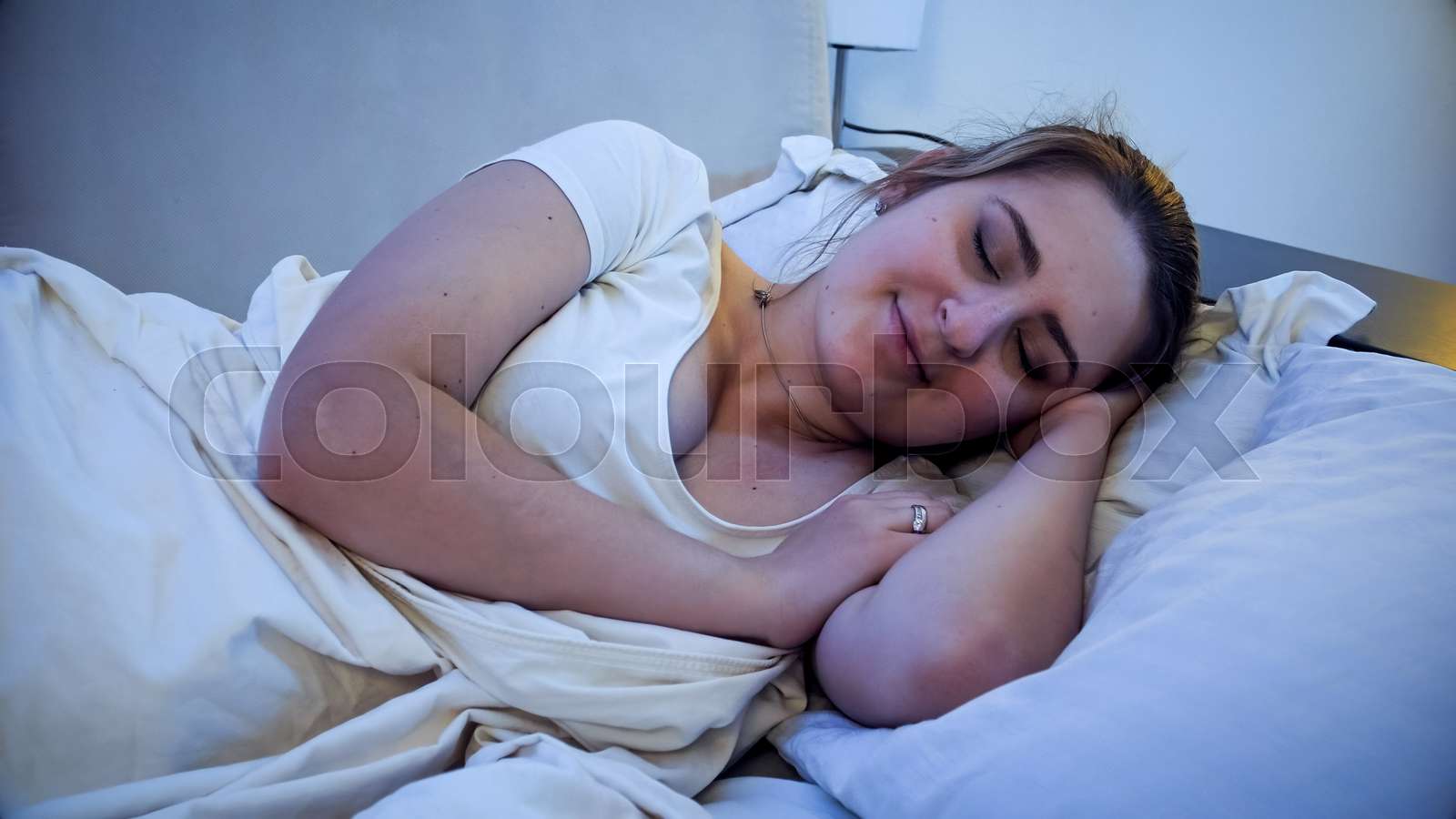 Closeup portrait of young beautiful woman sleeping in dark room at ...