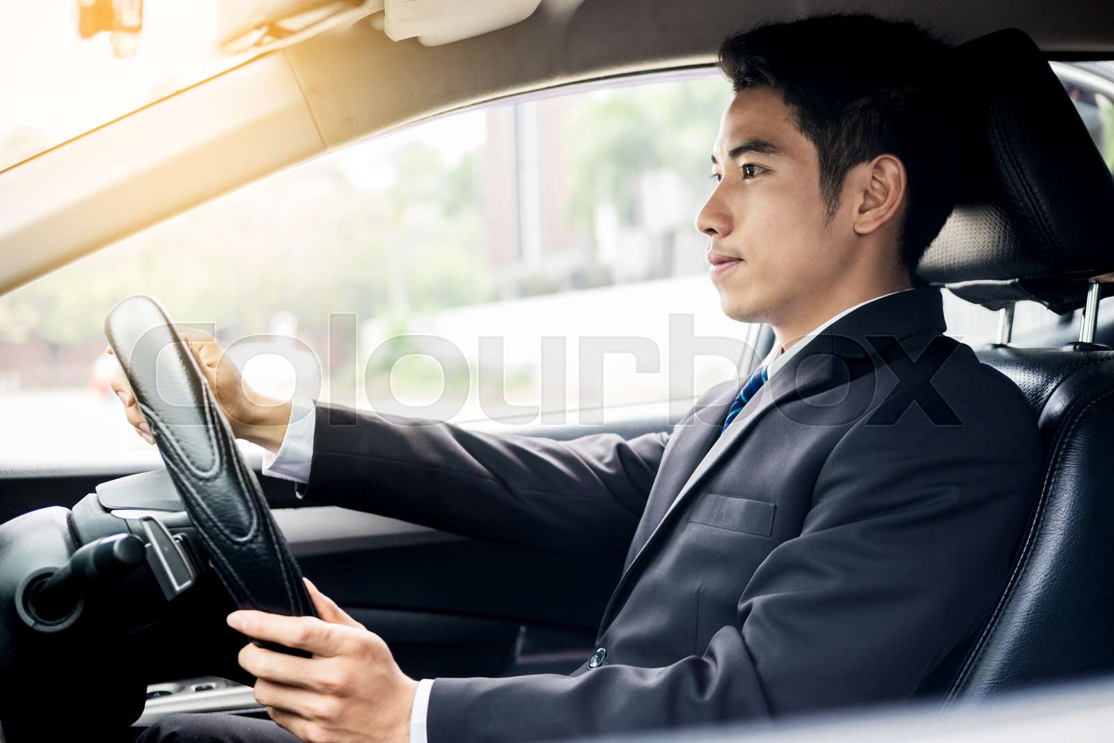 Portrait of a young handsome businessman driving a luxury sports car ...