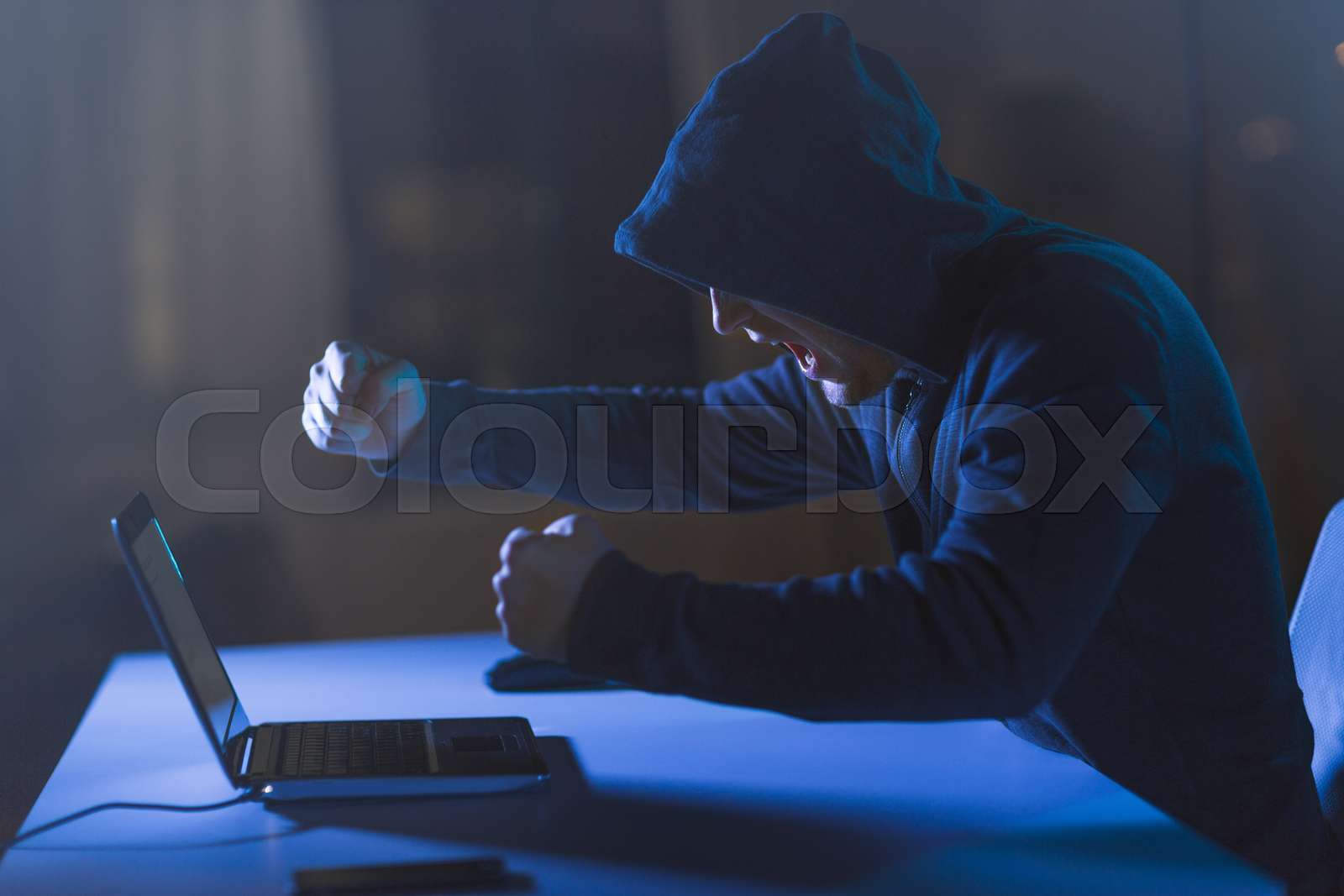 angry hacker with laptop shouting in dark room | Stock image | Colourbox